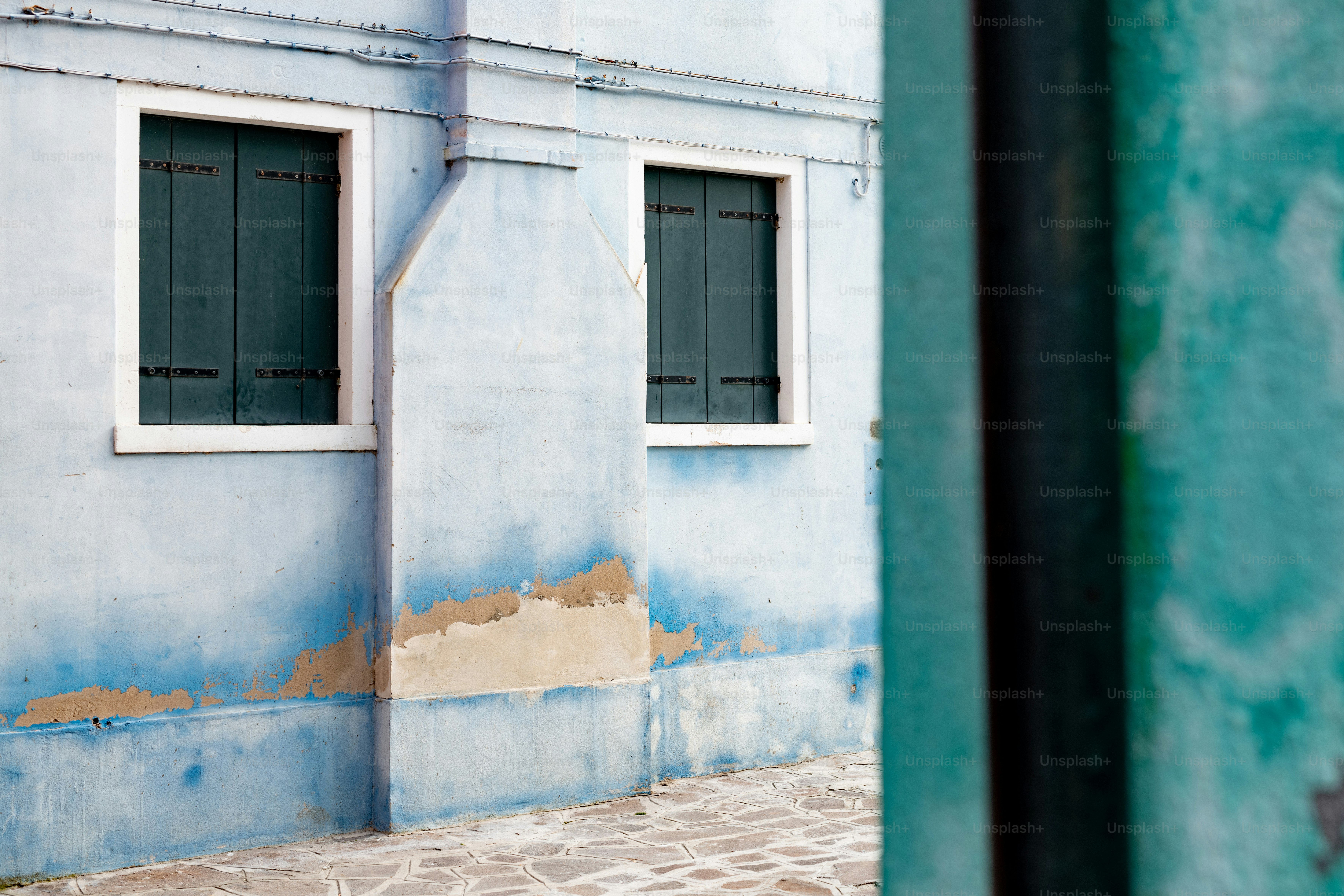 Un bâtiment bleu avec deux fenêtres sur le côté photo – Italie Photo ...