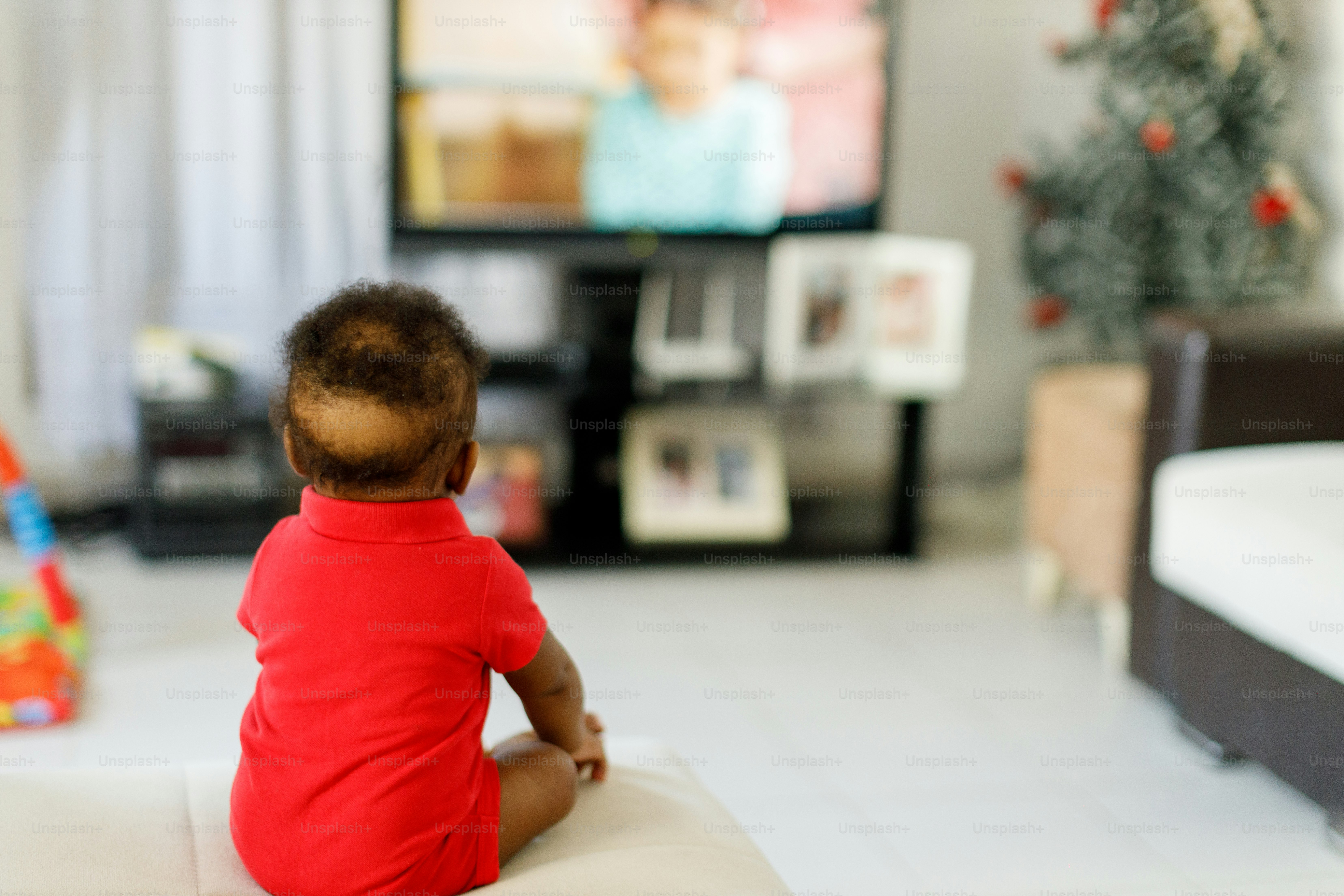 A baby sitting on a couch watching tv photo – Mother Image on Unsplash