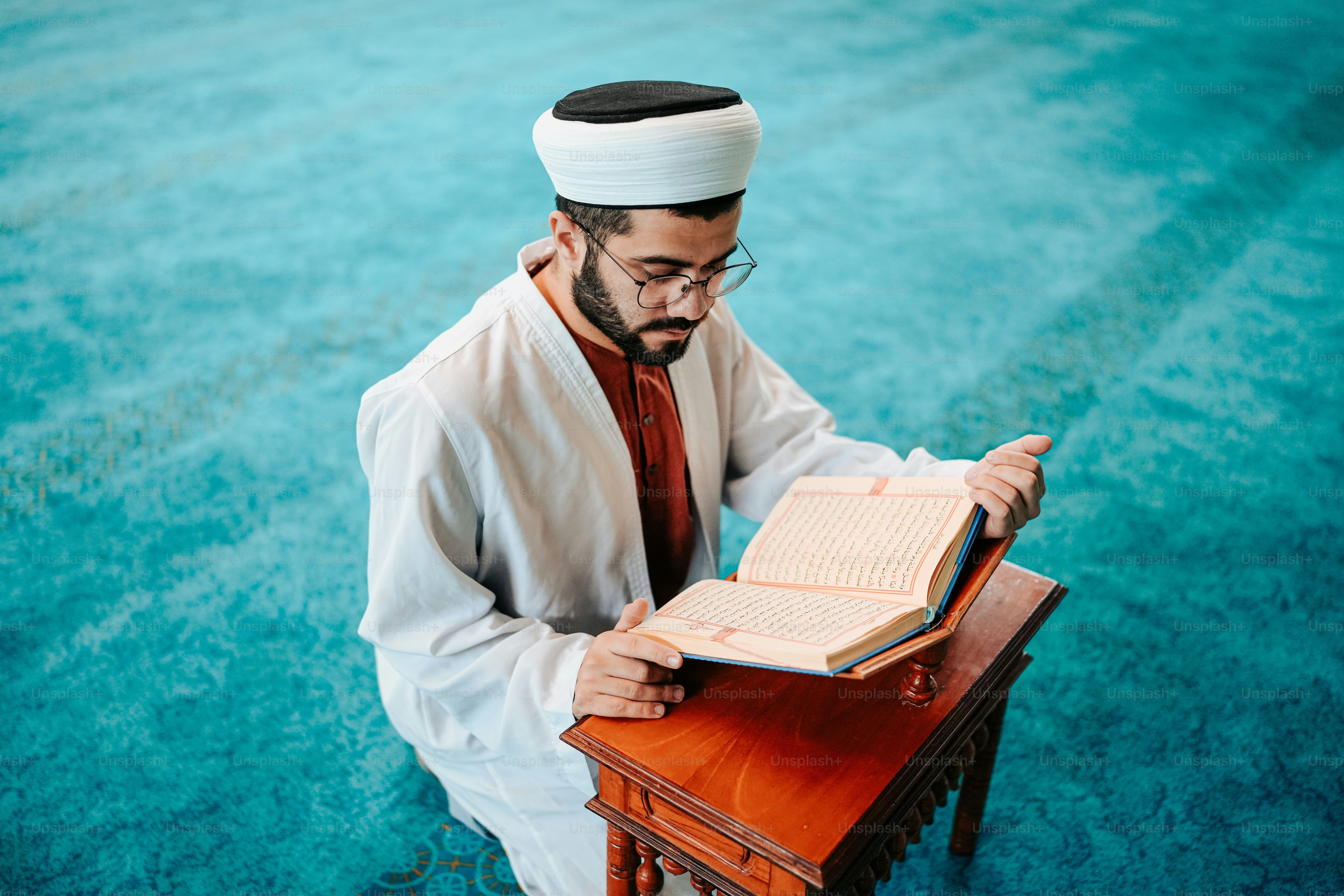 A man sitting at a desk with a book photo – Imam Image on Unsplash