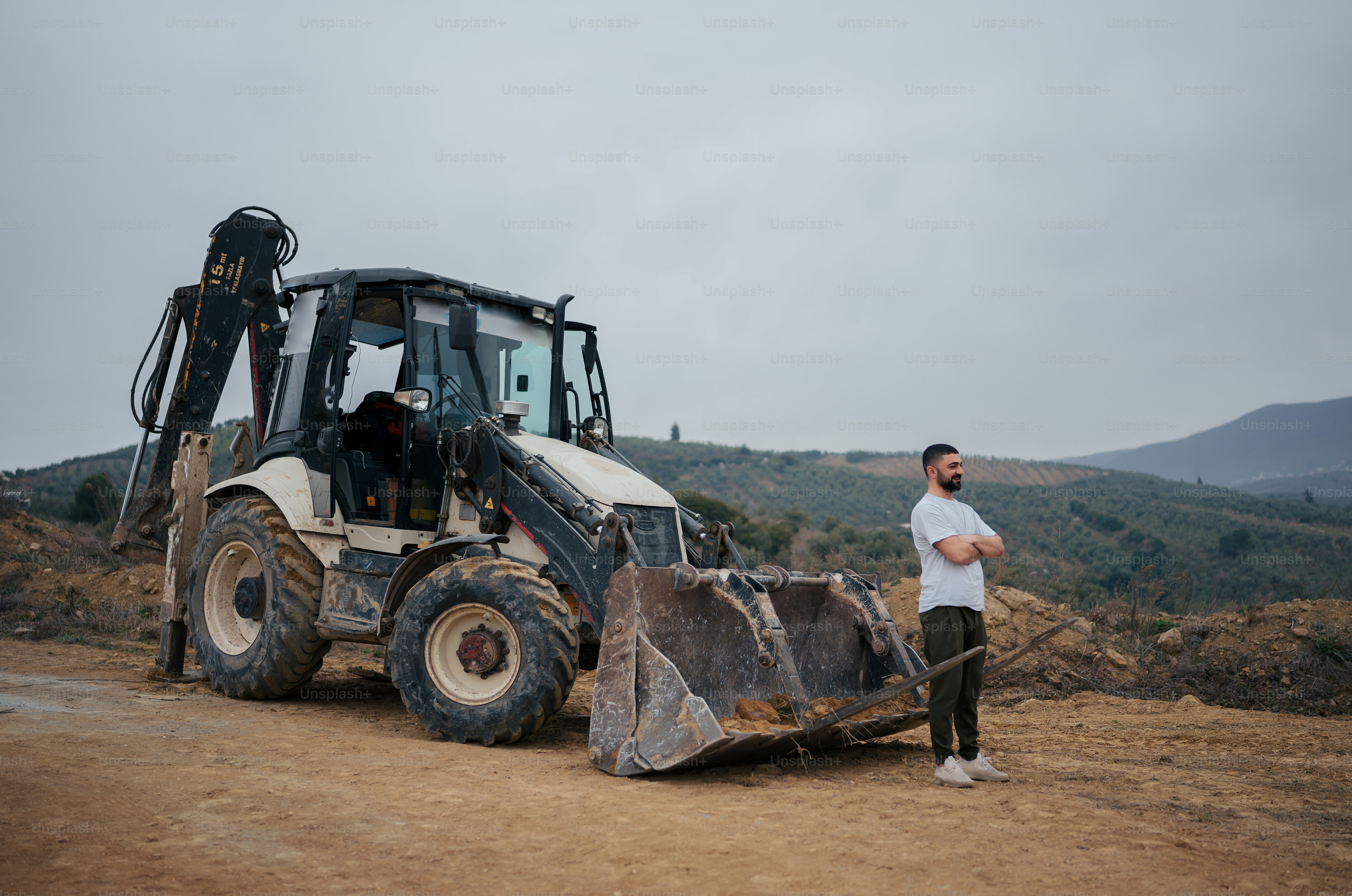 A man standing next to a bulldozer on a dirt road photo – Professional ...