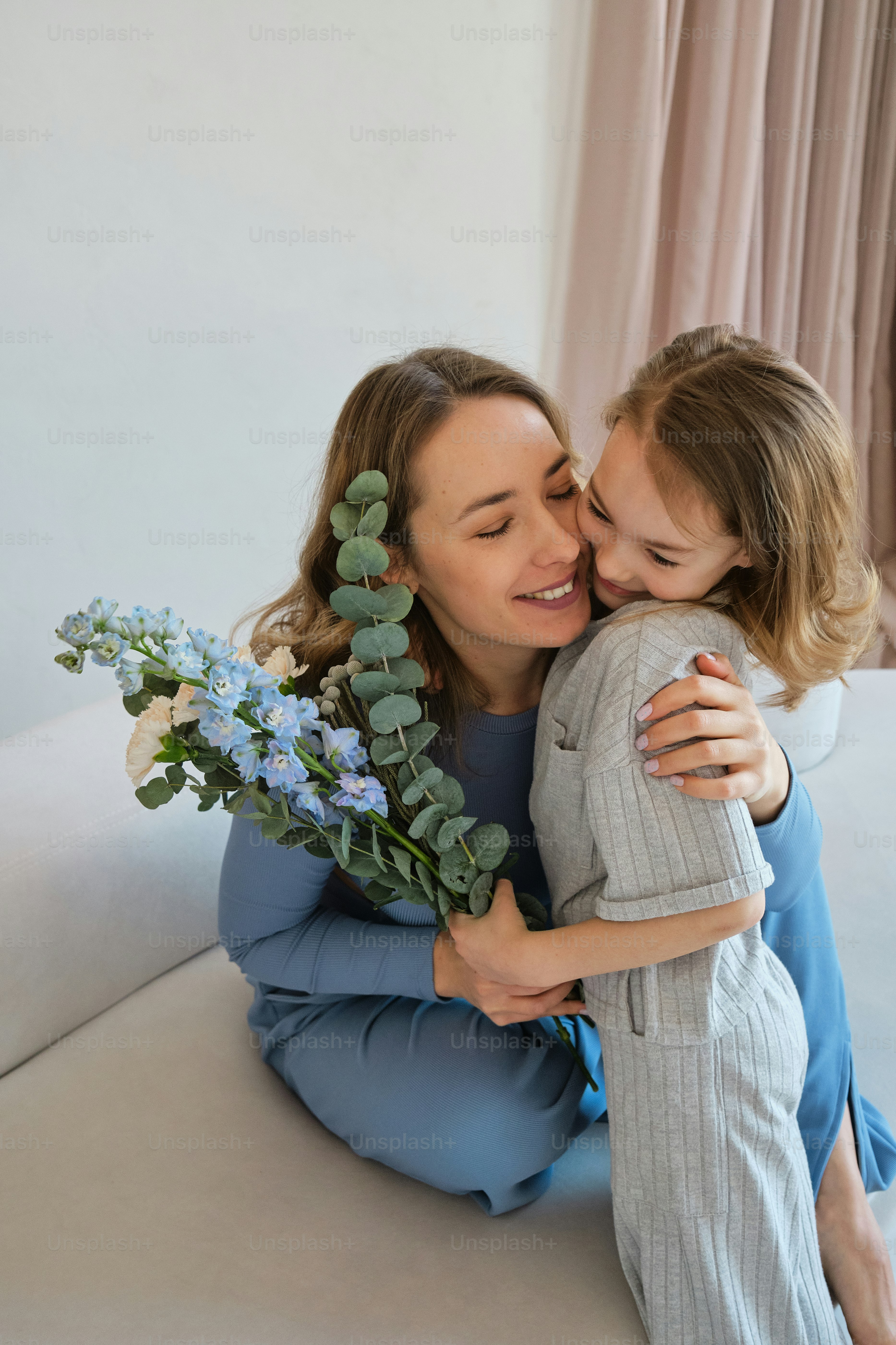 Foto zum Thema Eine Frau umarmt ein kleines Mädchen auf der Couch ...