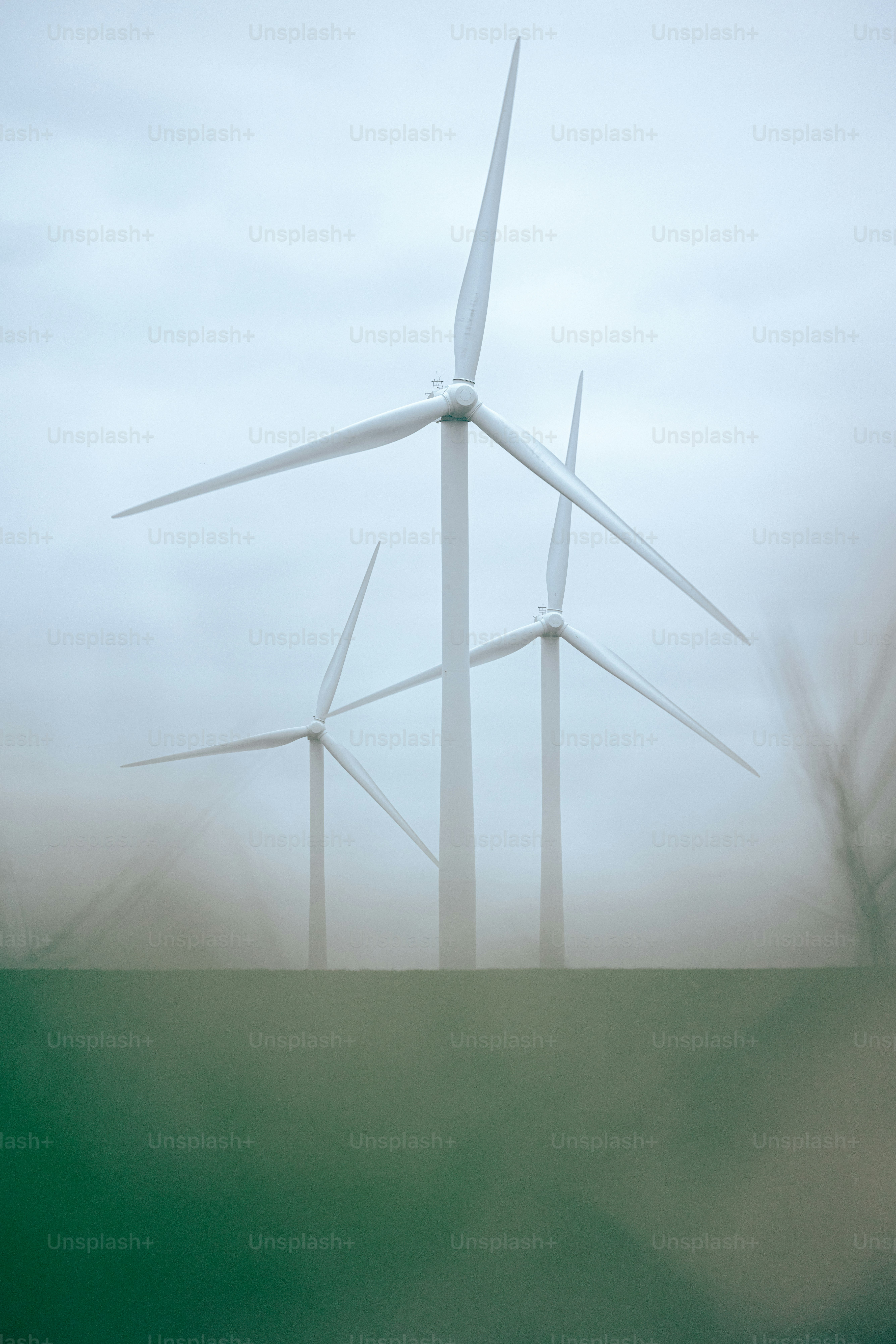 A group of wind turbines on a foggy day photo – Renewable energy Image ...