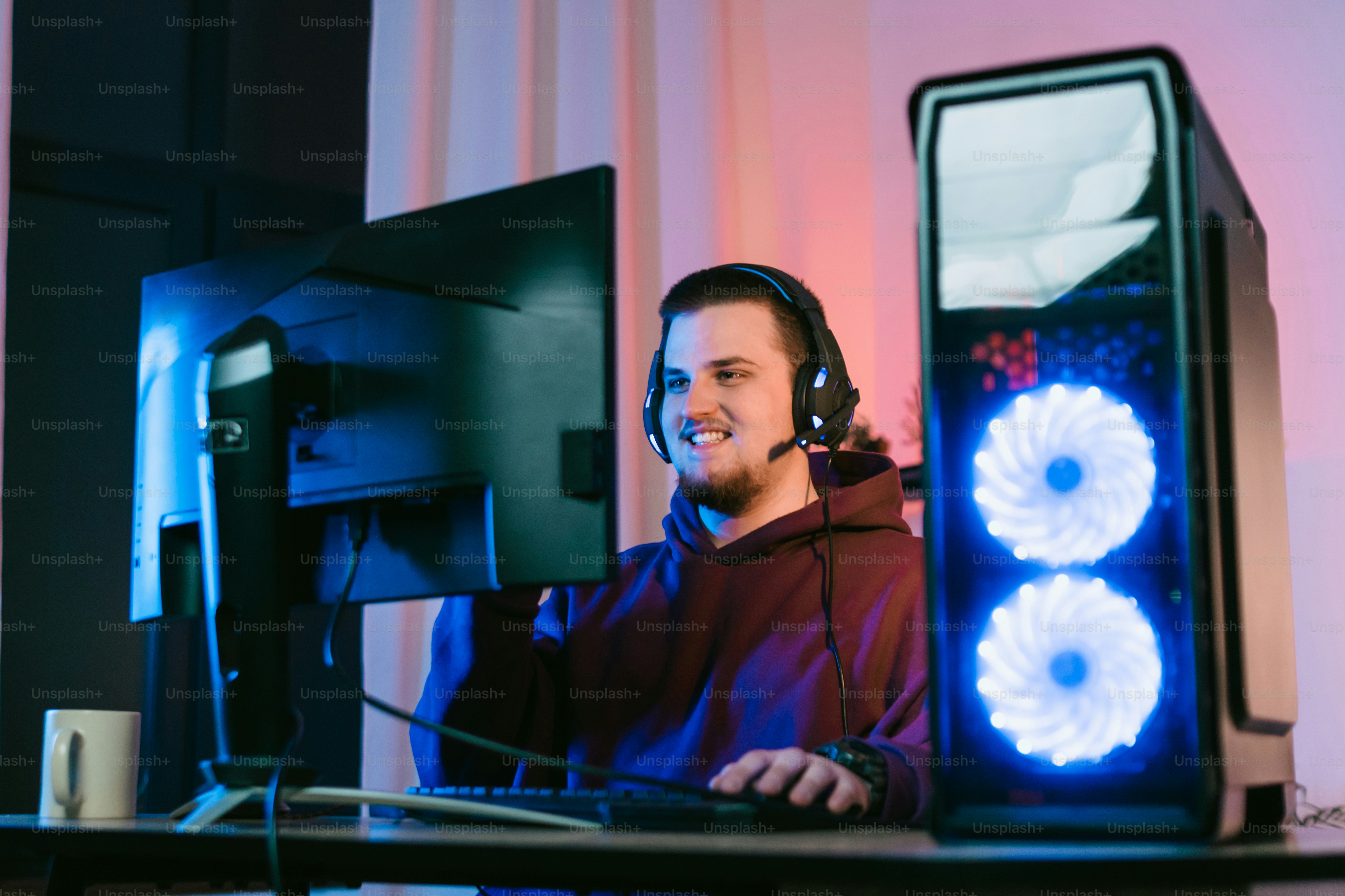 A man wearing headphones sitting in front of a computer photo – Online ...