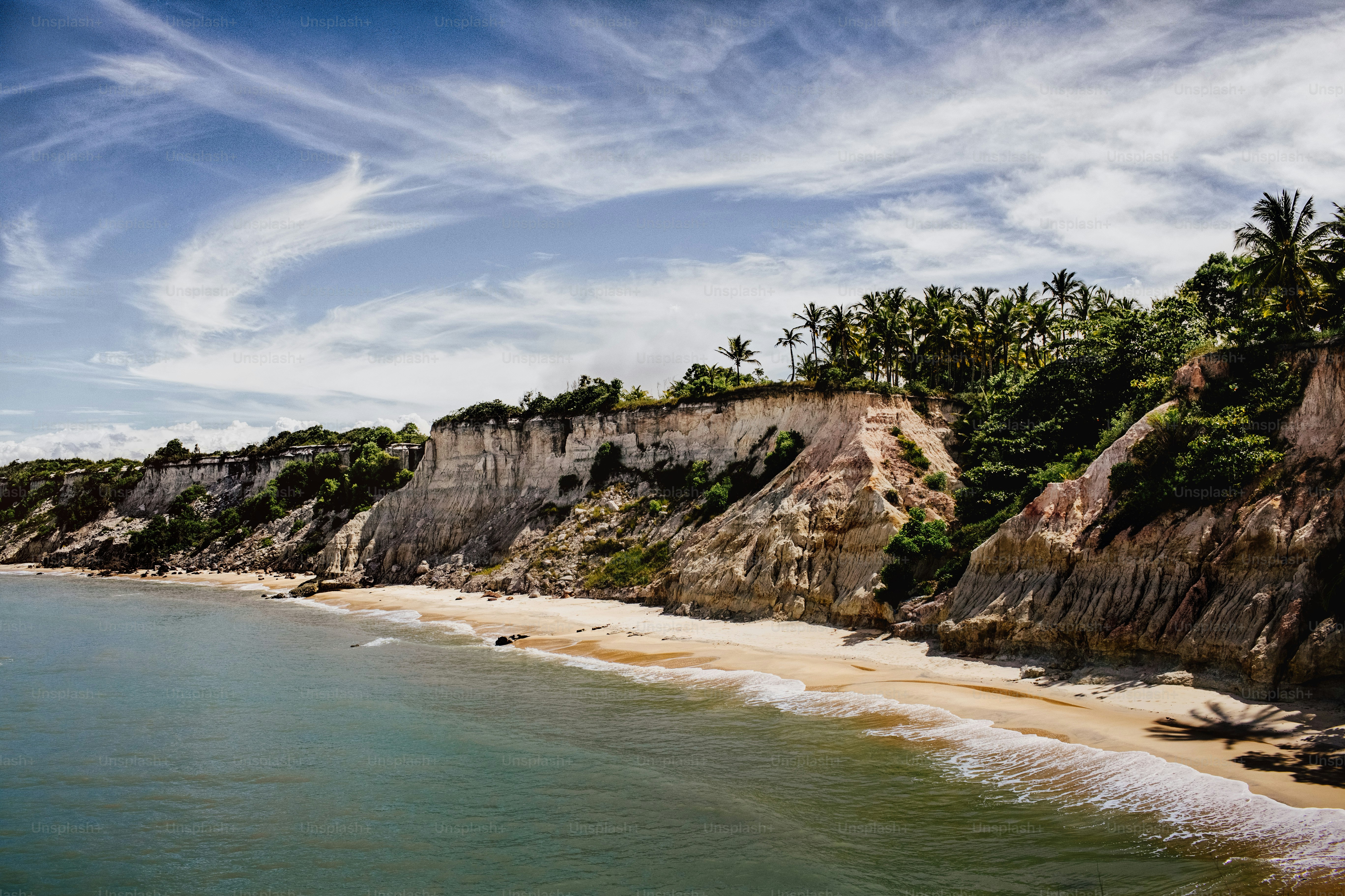 A view of a beach with a cliff in the background photo – Beach Image on ...