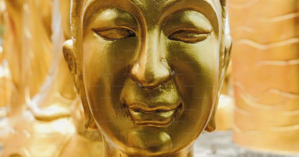 他の仏像の前に座っている黄金の仏像の写真 Unsplashのムルティの画像