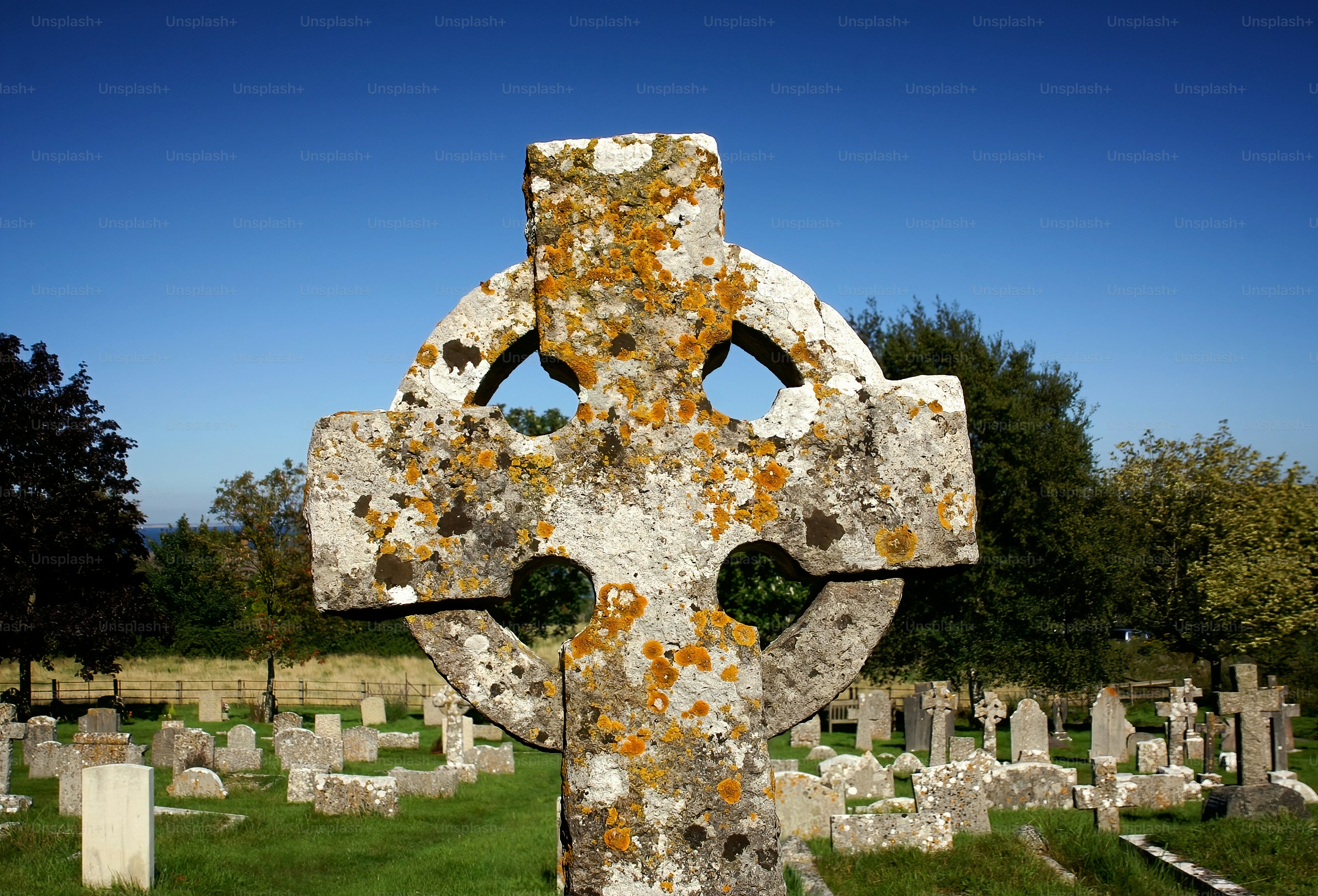 A stone cross with carvings on it against a blue sky photo – Stone ...