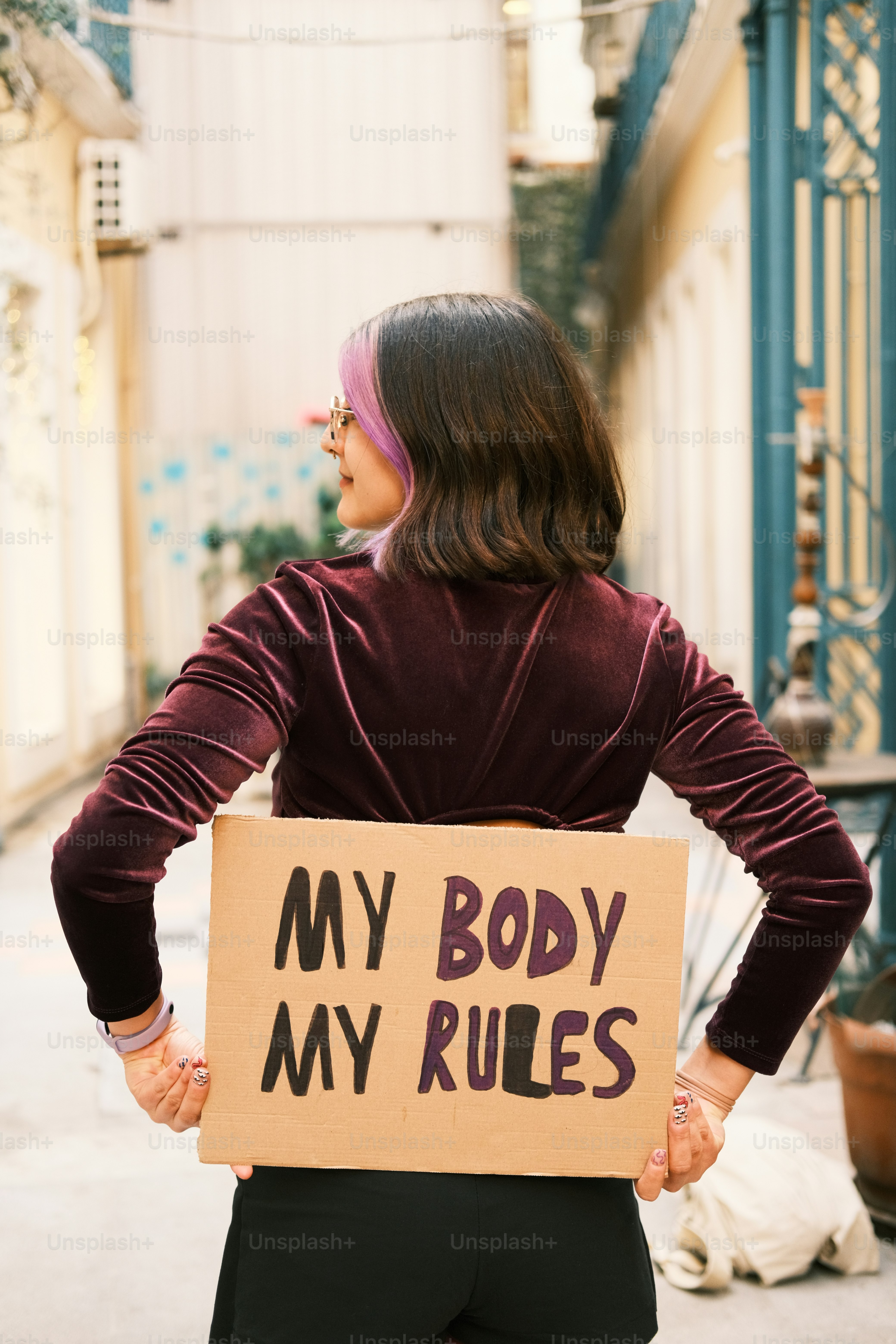 A woman holding a cardboard sign that says, my body my rules photo ...