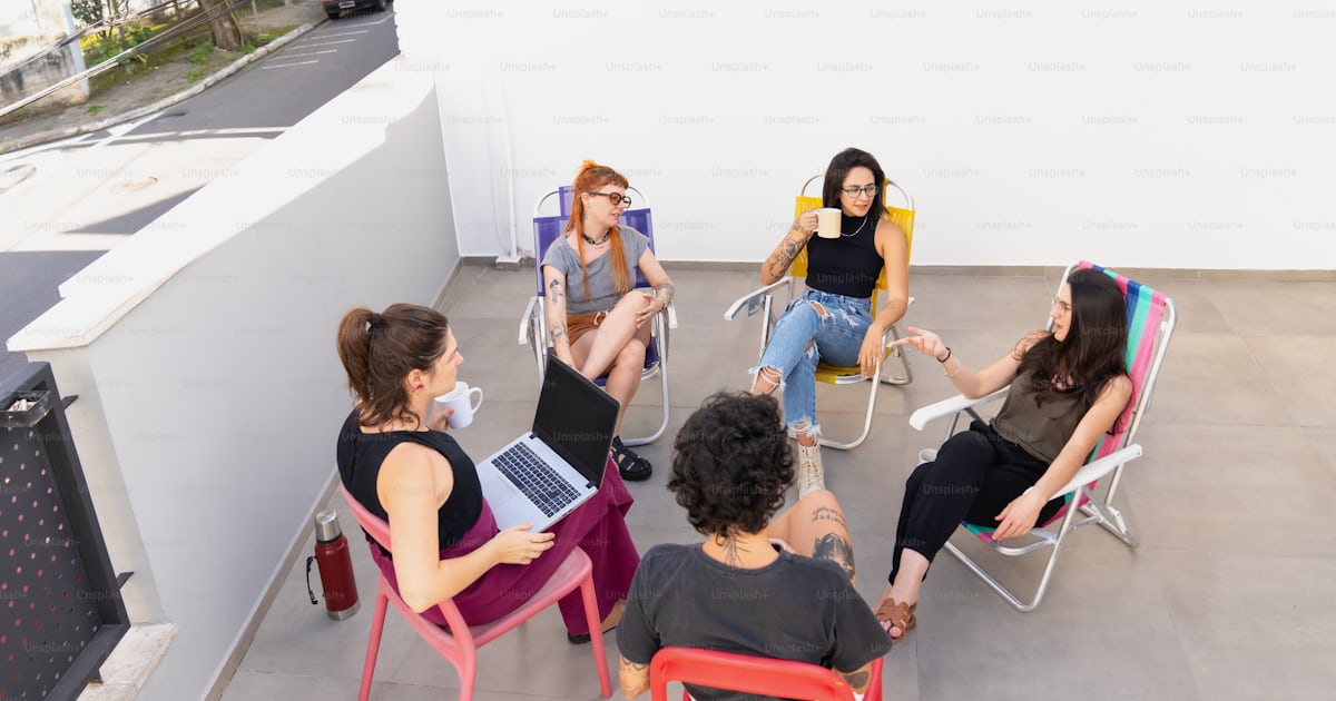 Un Grupo De Mujeres Sentadas Una Alrededor De La Otra En Sillas Foto
