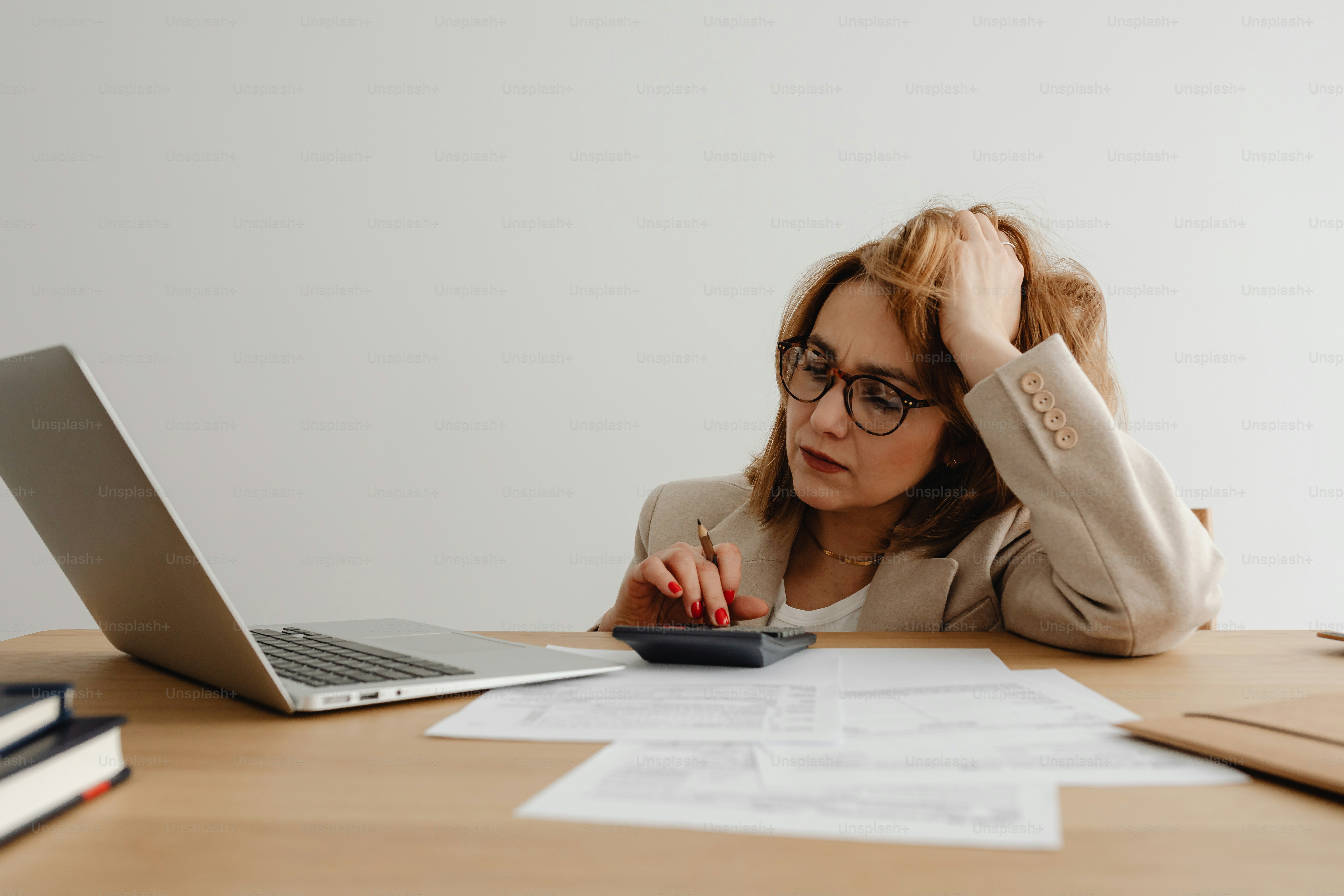 A woman sitting at a desk with a laptop photo – Tax return Image on ...