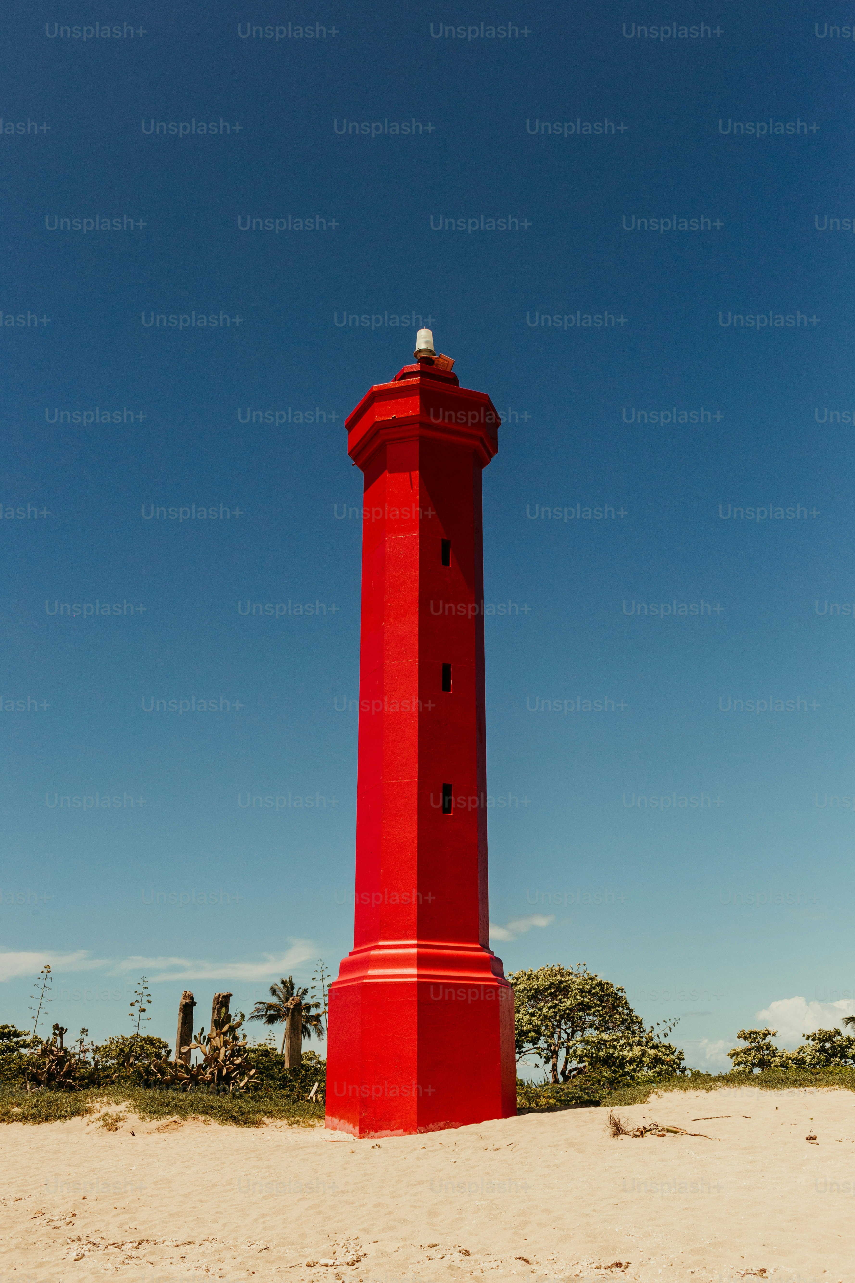 Un faro rojo en una playa de arena bajo un cielo azul foto – Imagen de ...