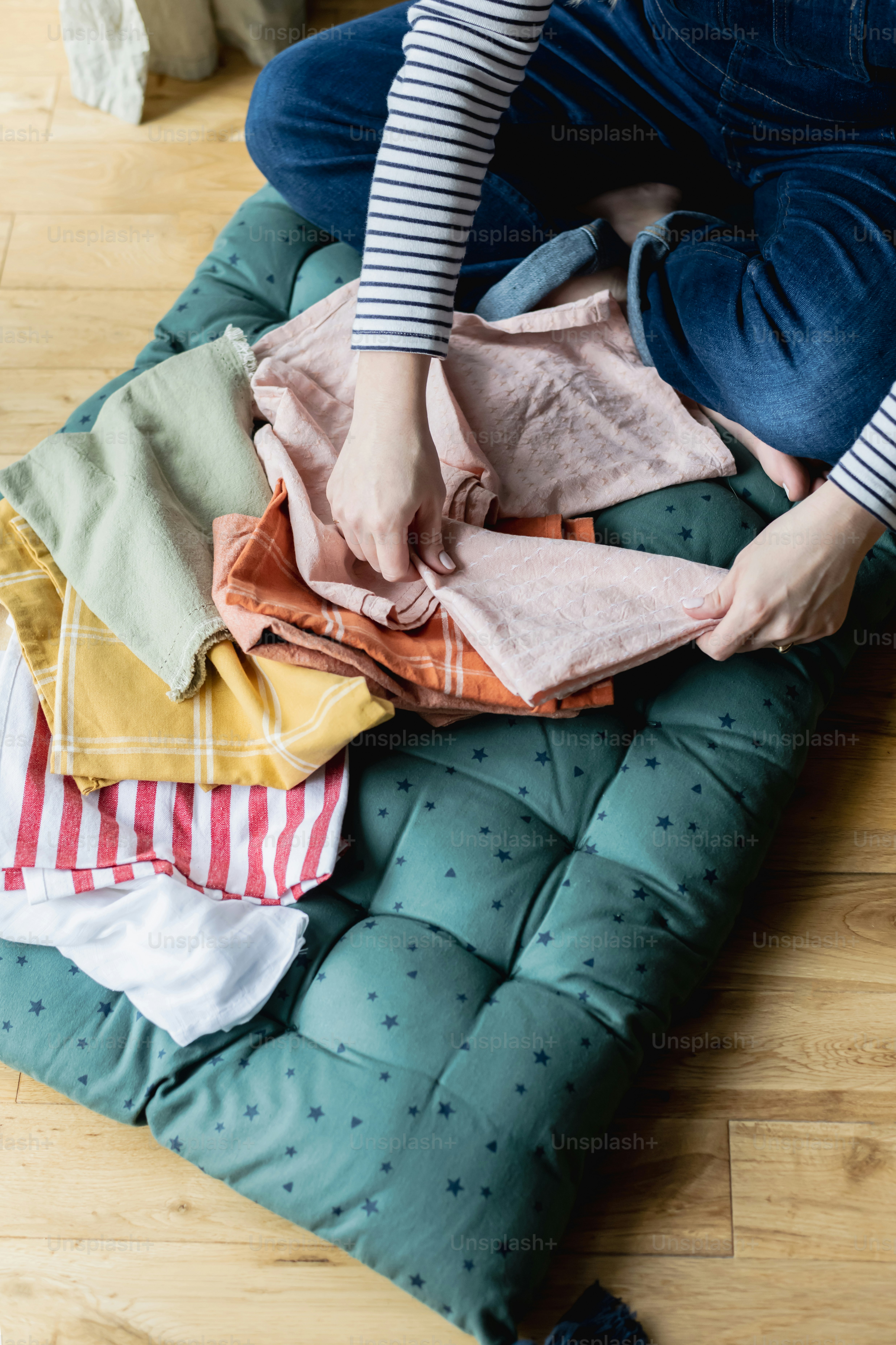 A woman sitting on a mattress with clothes on it photo – Cleaning Image ...