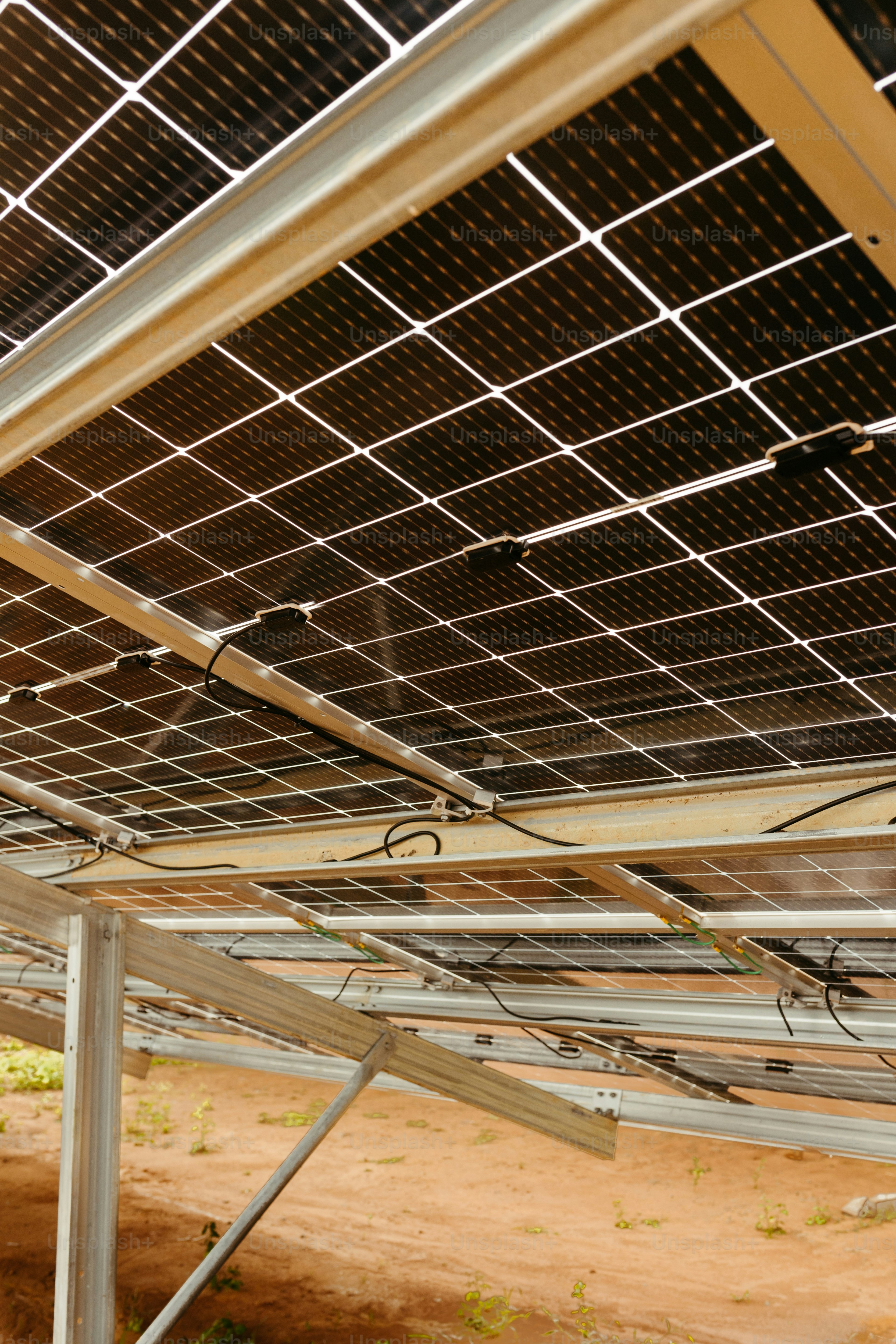 A row of solar panels in a dirt field photo – Solar energy Image on ...
