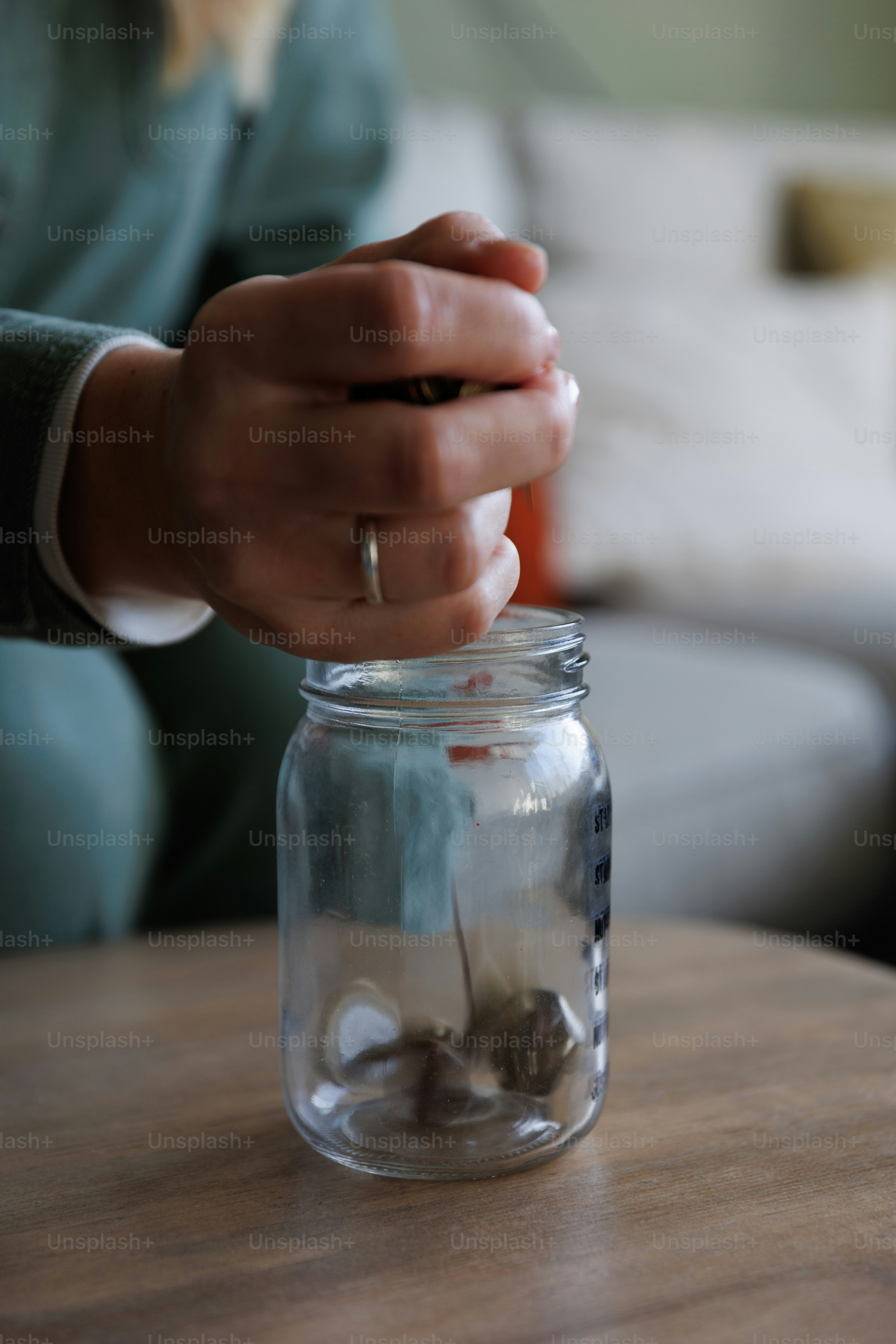 A person putting coins in a jar on a table photo – Inflation Image on ...