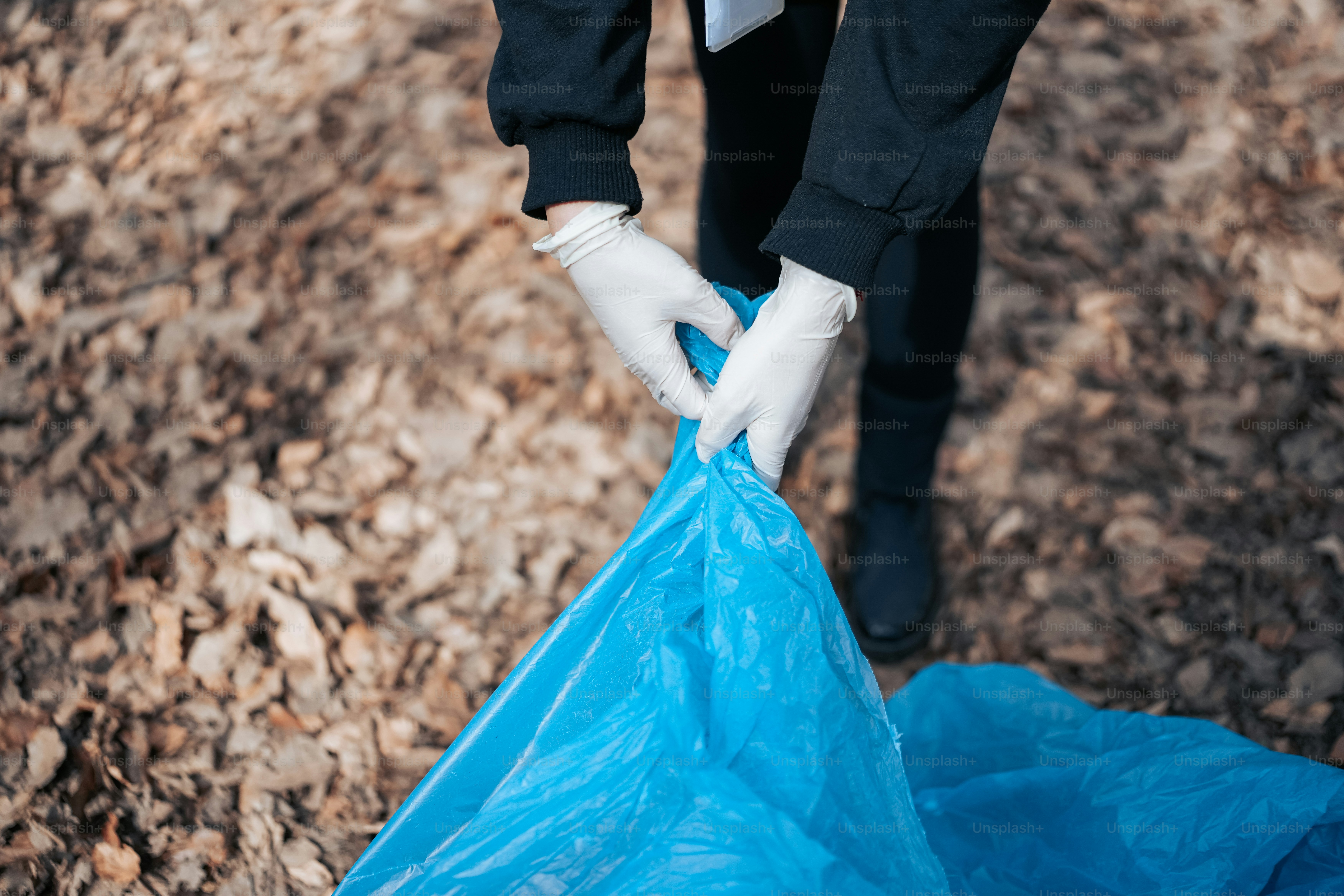 A man in a suit and white gloves holding a blue plastic bag photo ...