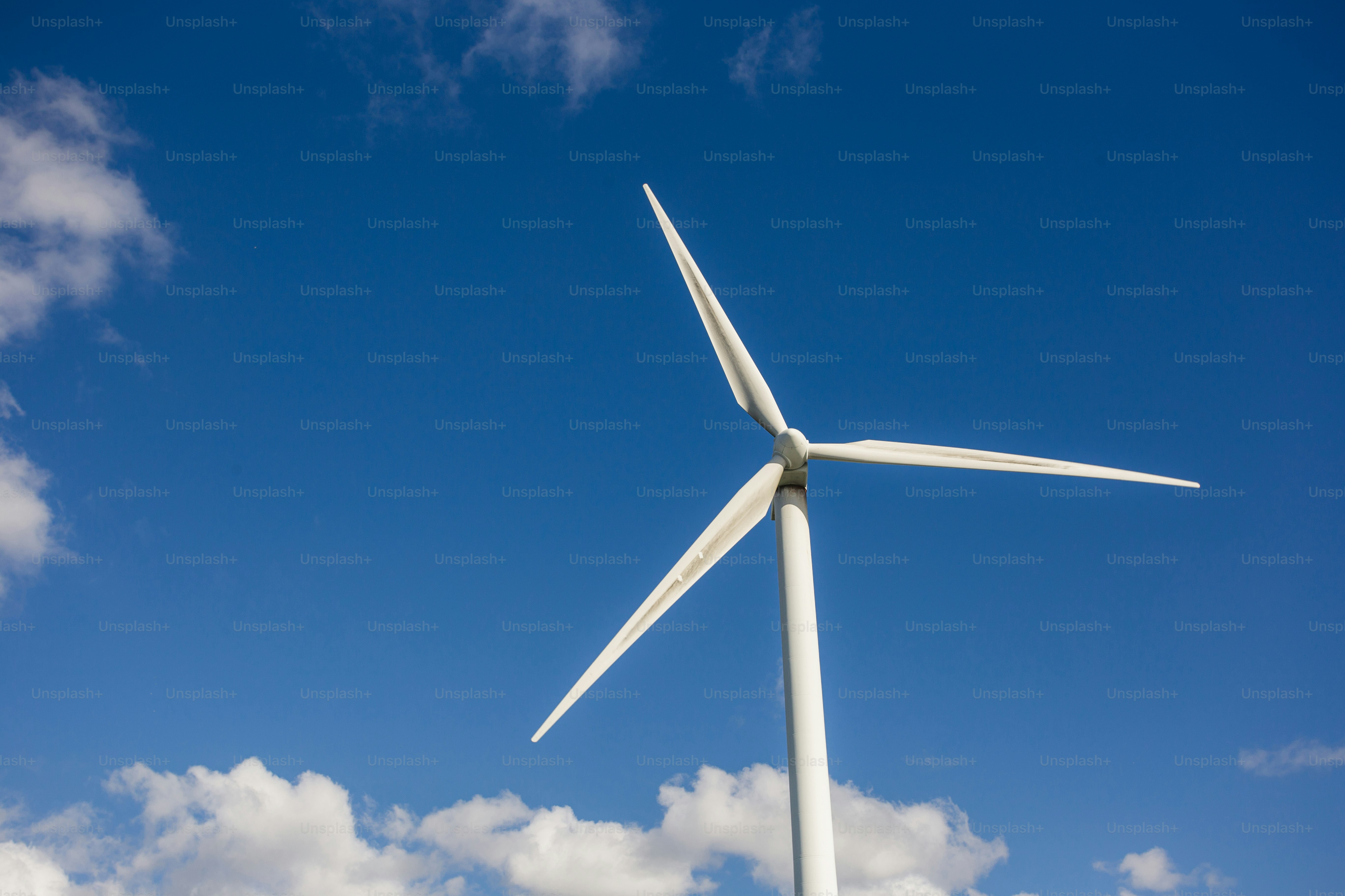 A wind turbine is shown against a blue sky photo – Green energy Image ...