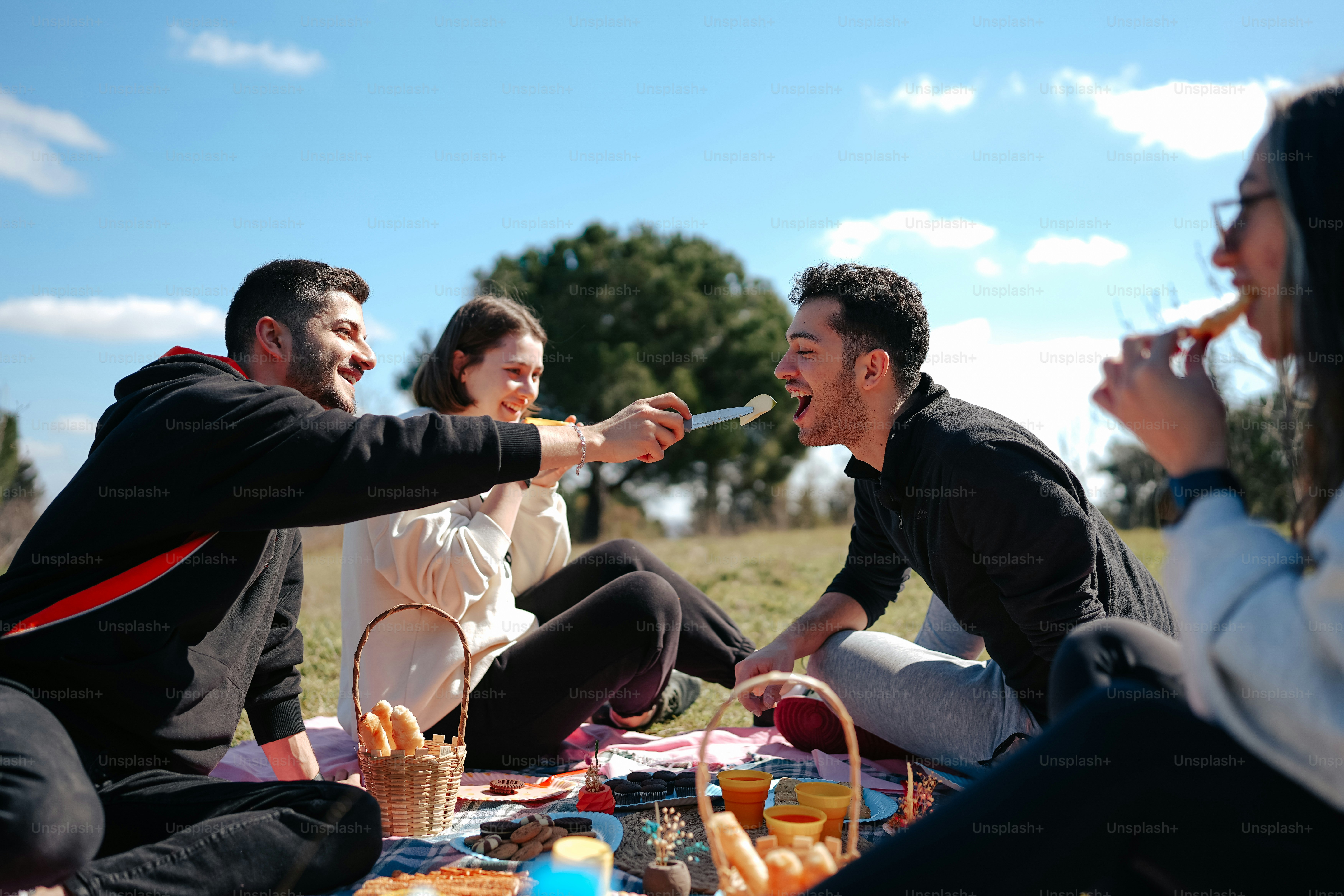 A group of people sitting on the ground eating food photo – Sharing ...