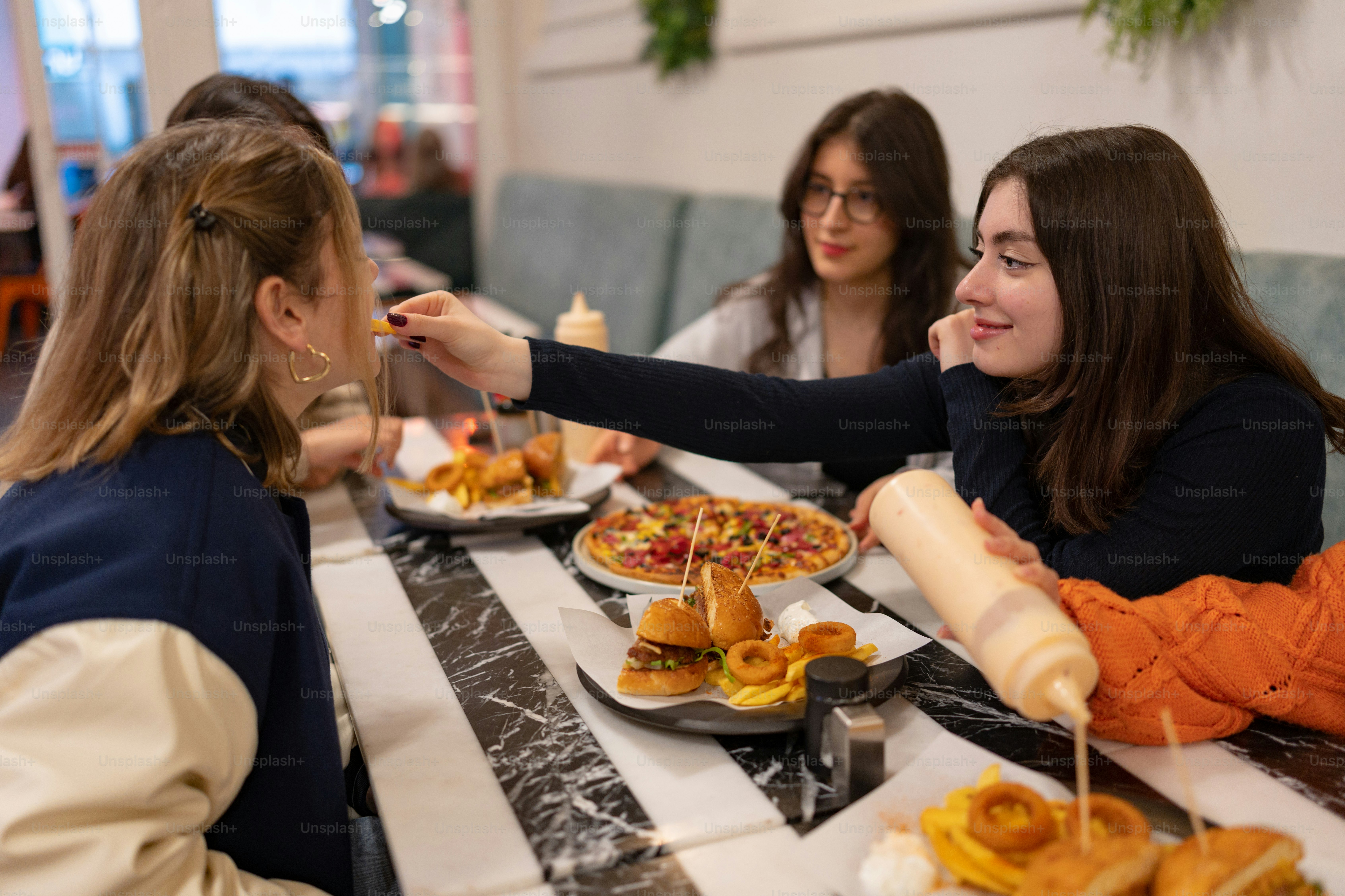 A group of women sitting at a table eating food photo – Food and drink ...