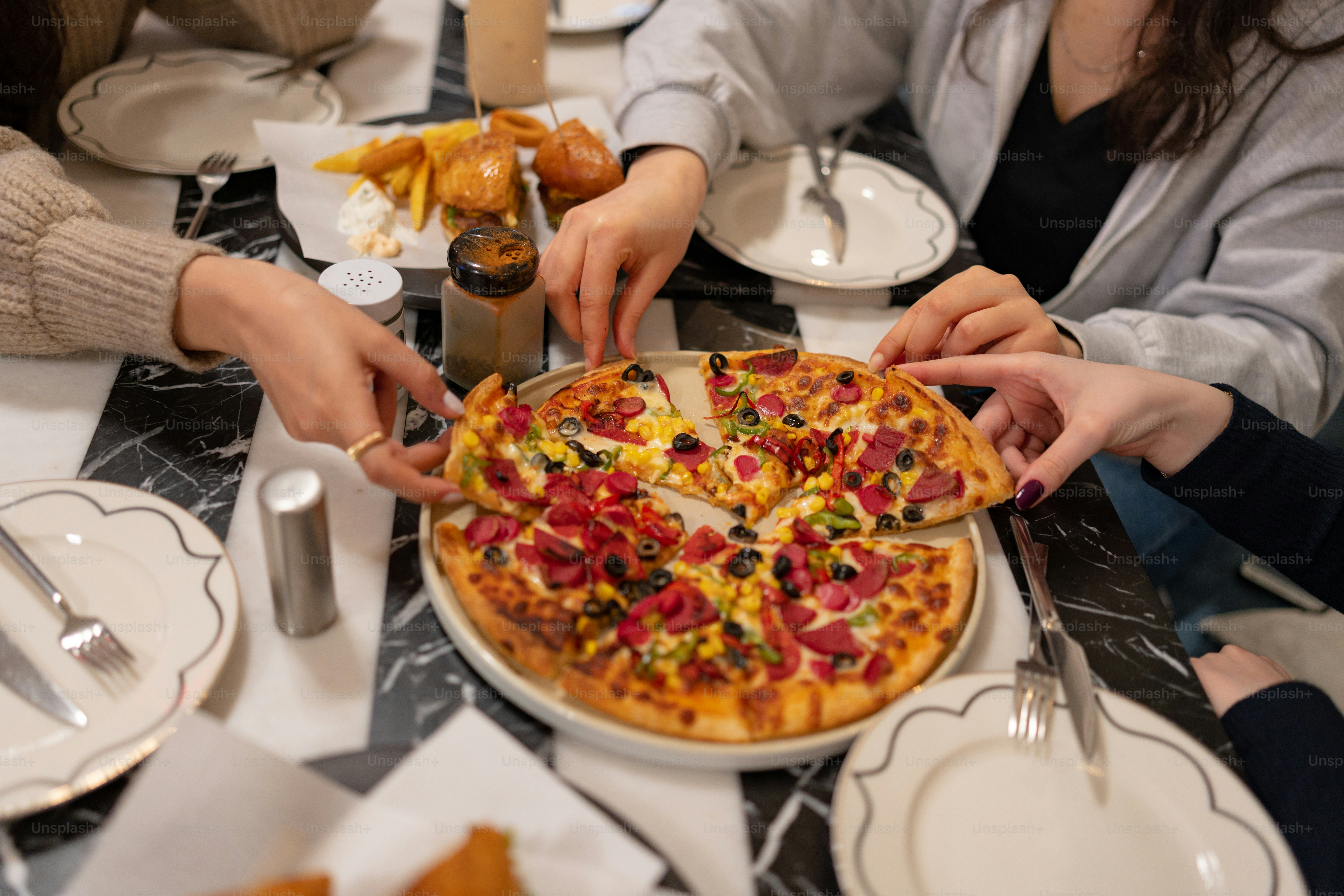A group of people sitting around a table eating food photo – Eating ...