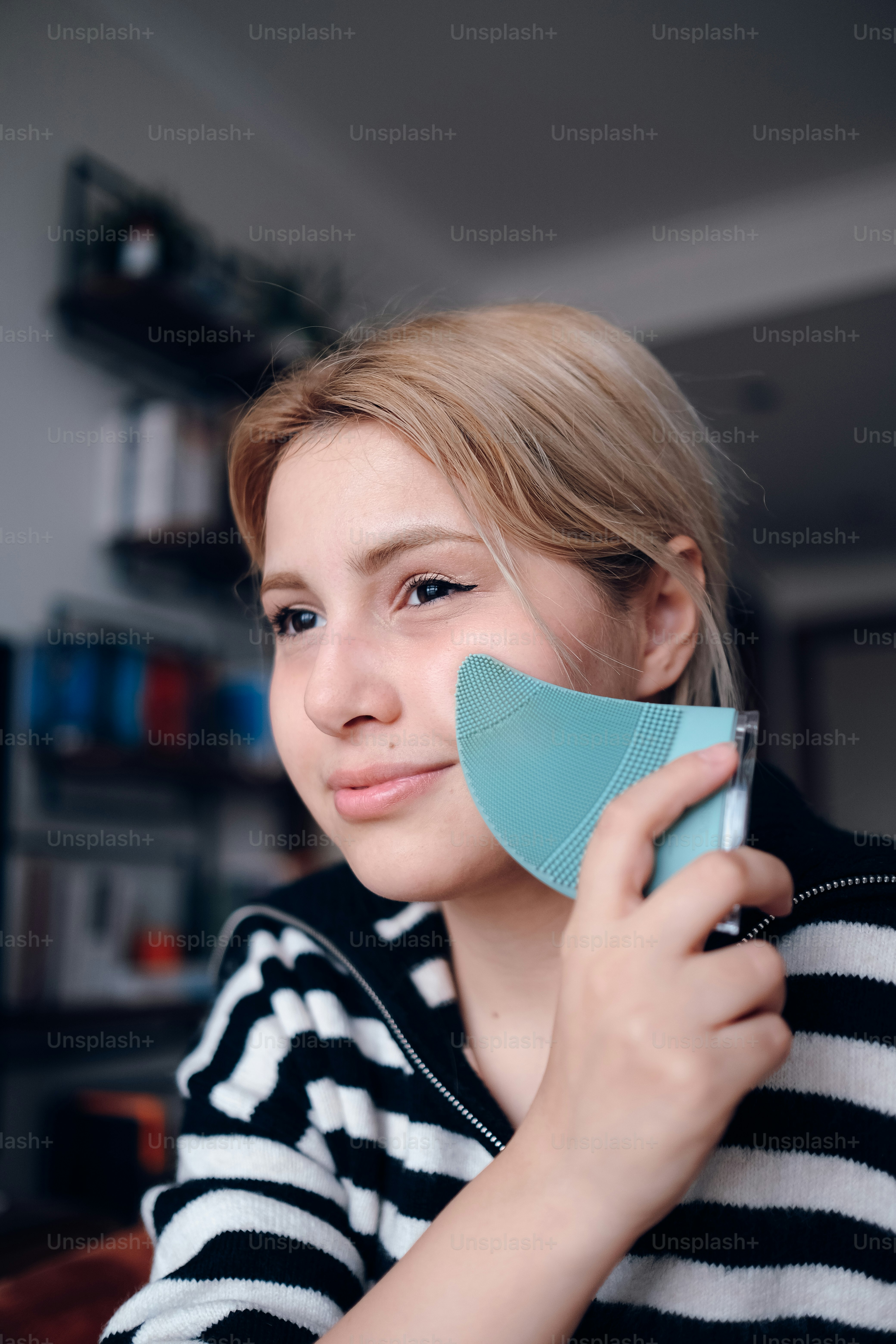 A young woman holding a blue object in her hand photo – Personal care ...