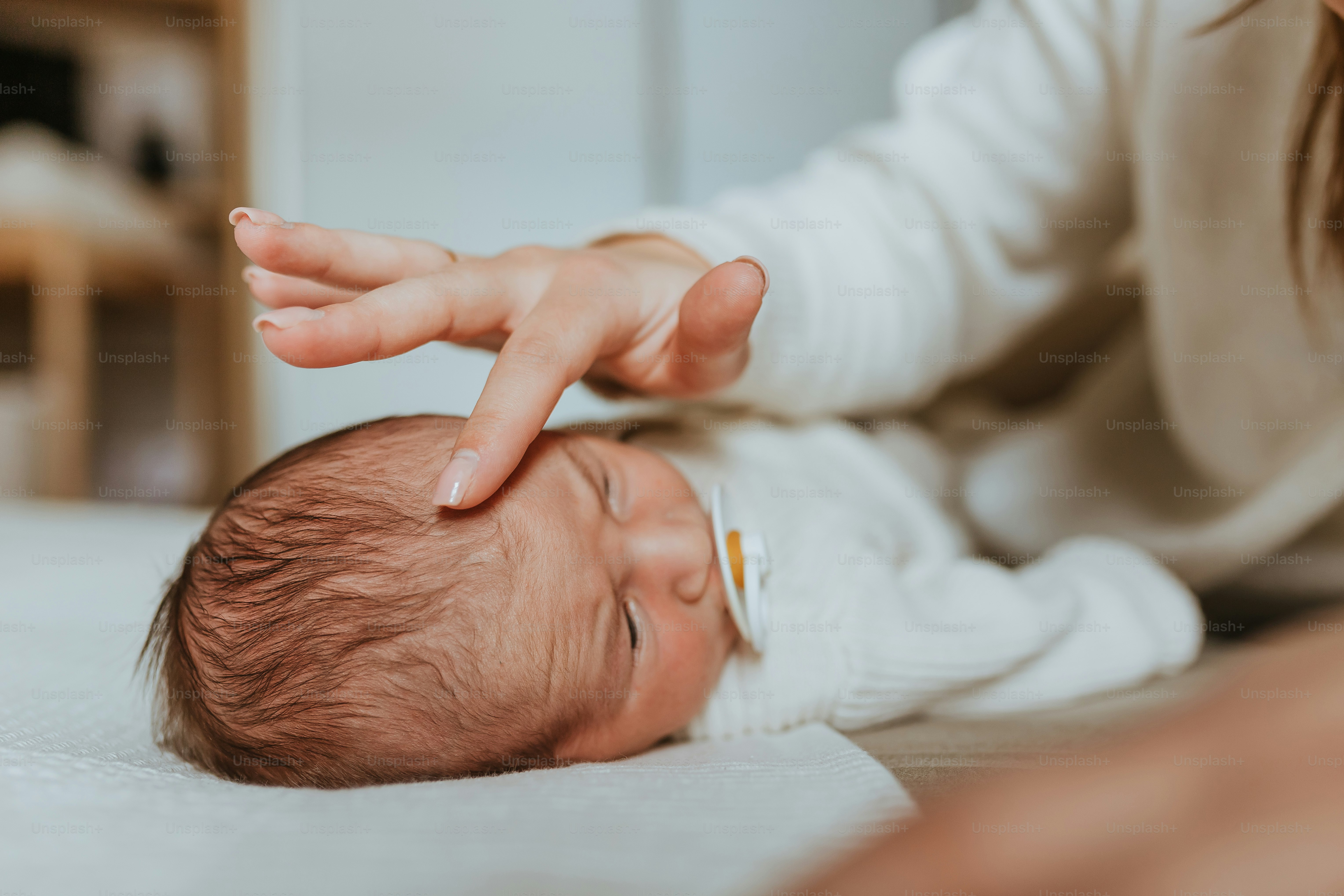 A close up of a person touching a baby's head photo – Touching baby ...