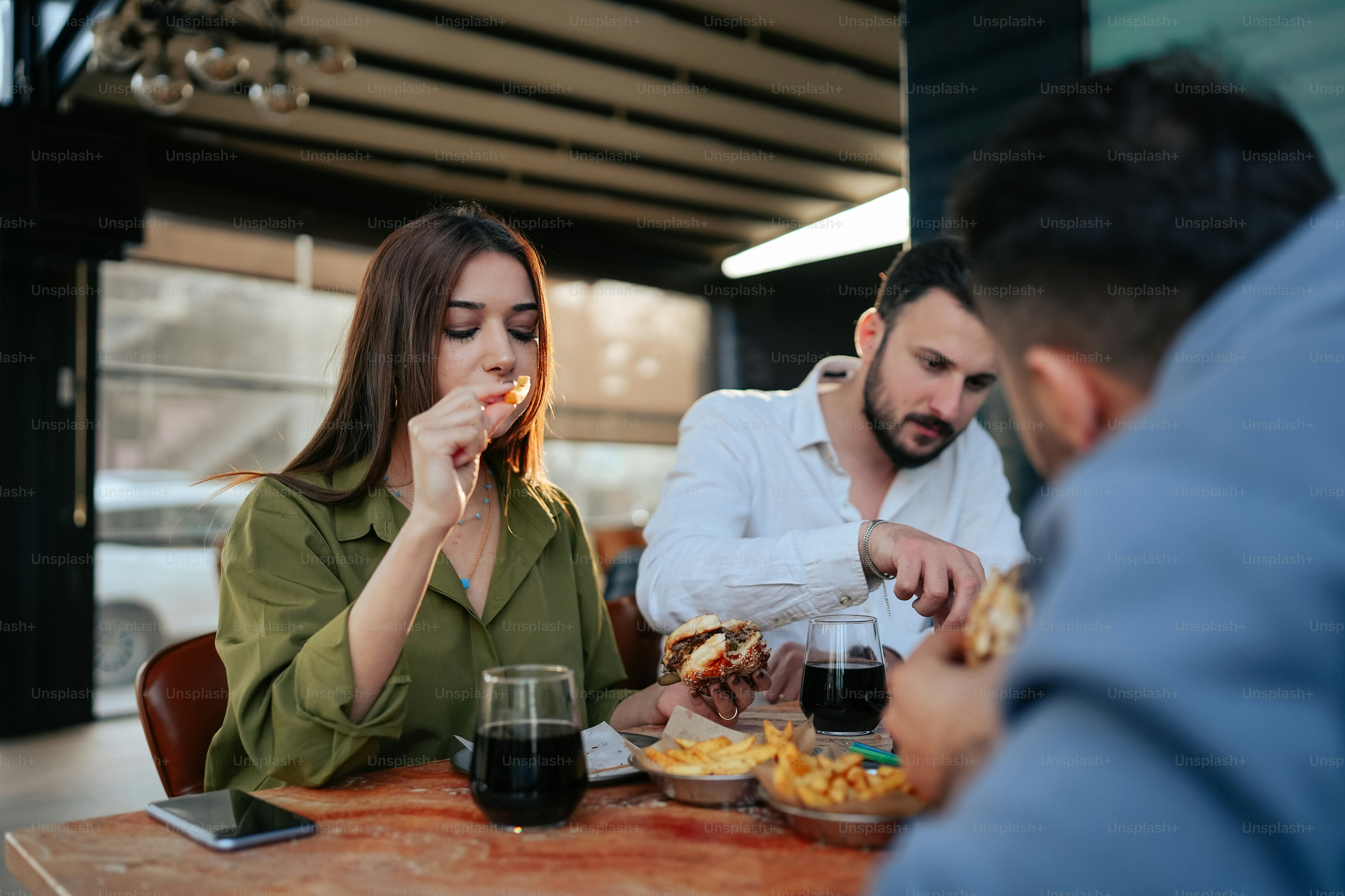 A group of people sitting around a wooden table eating food photo ...