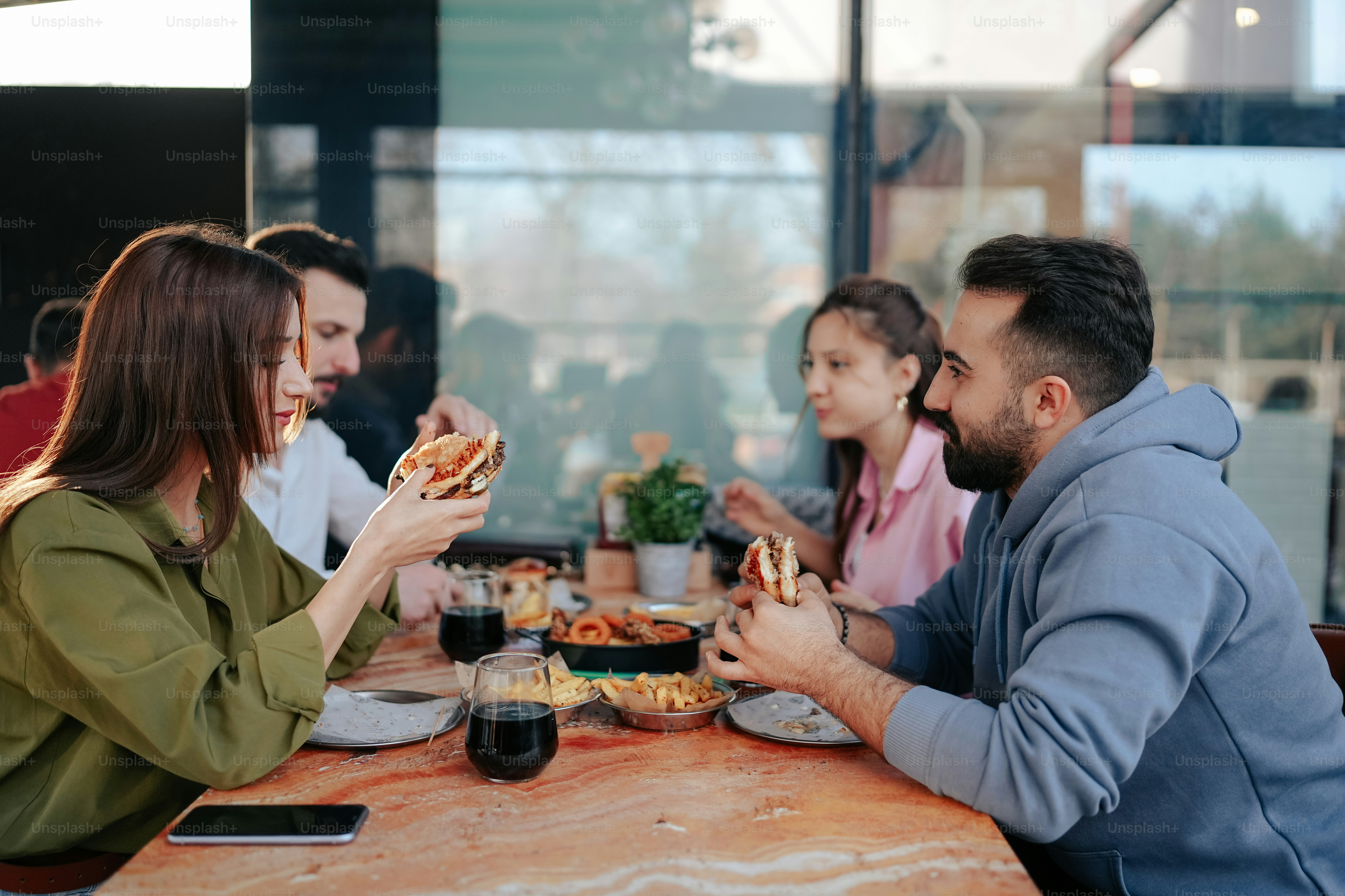 A group of people sitting at a table eating pizza photo – Eating out ...