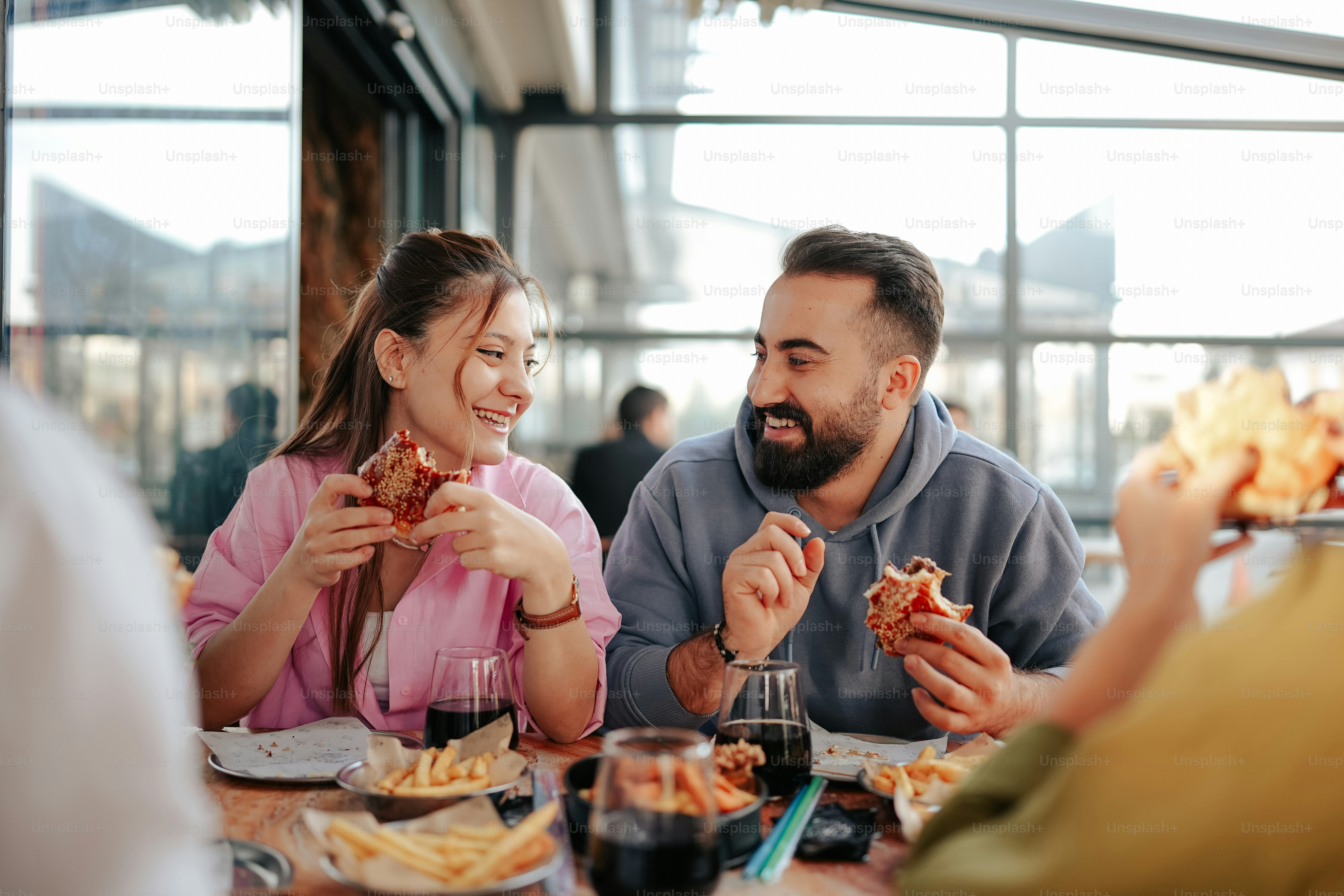A group of people sitting around a table eating pizza photo – Eating ...