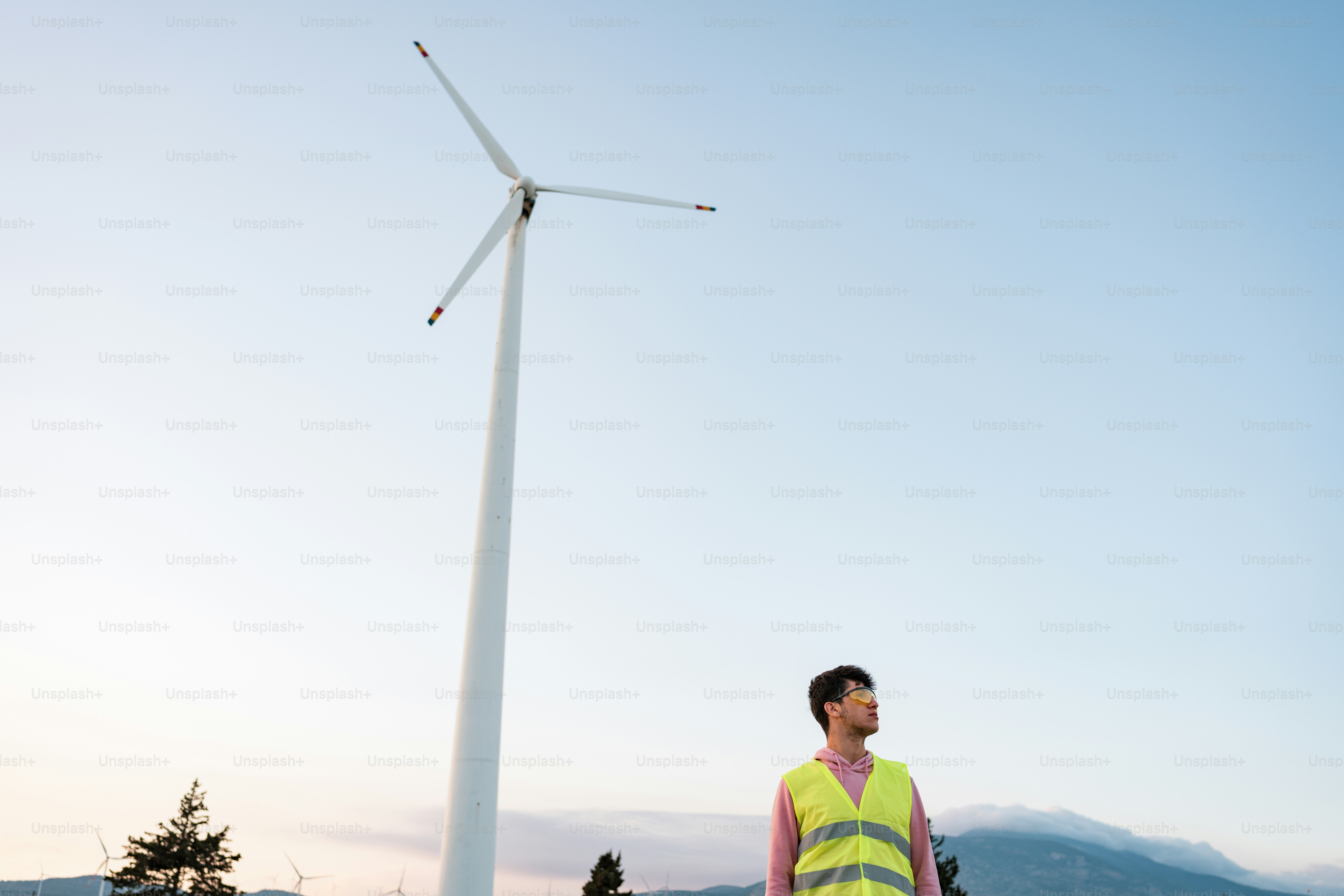 A man standing next to a wind turbine photo – Wind power Image on Unsplash