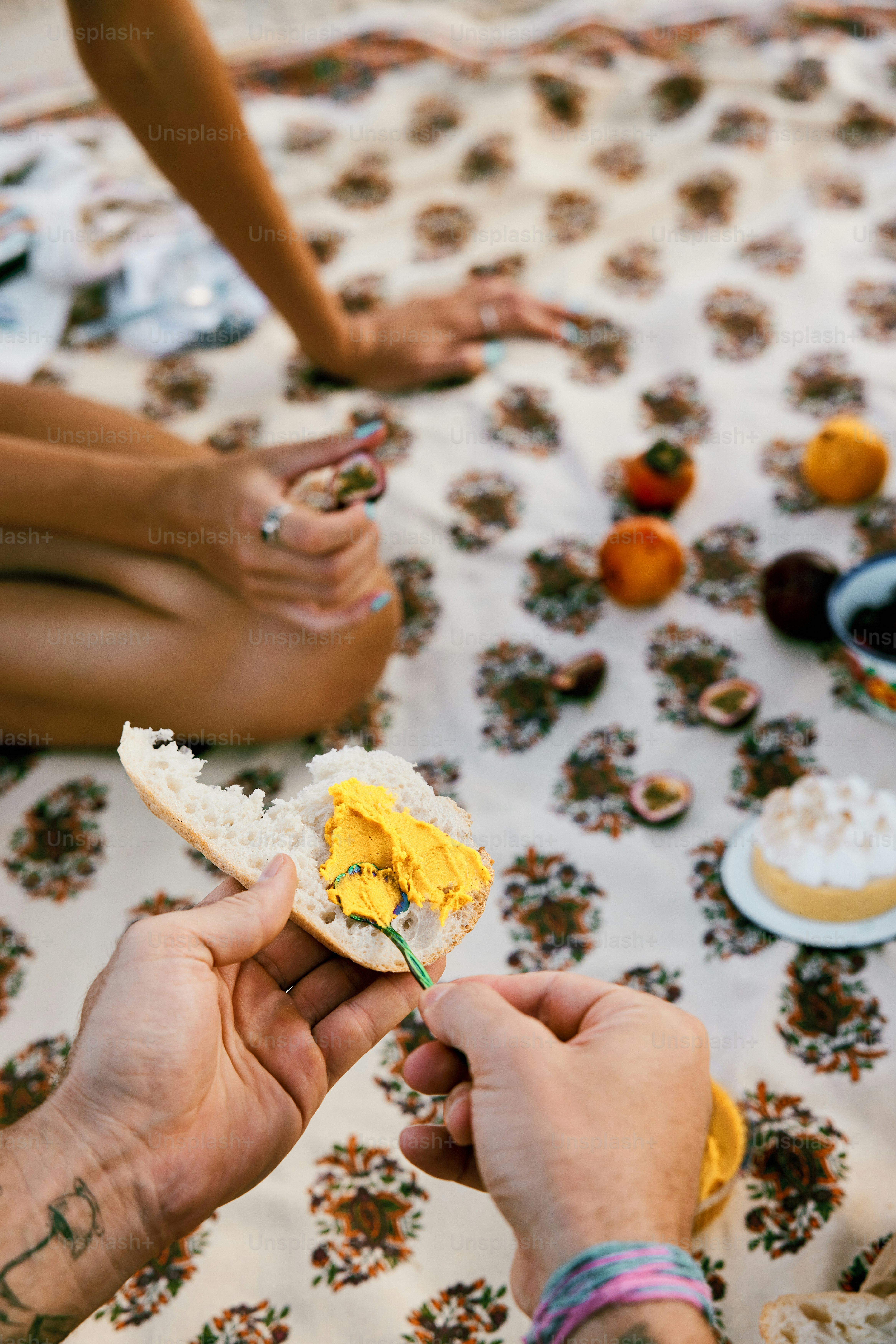 A group of people sitting on top of a bed eating food photo – Picnic ...
