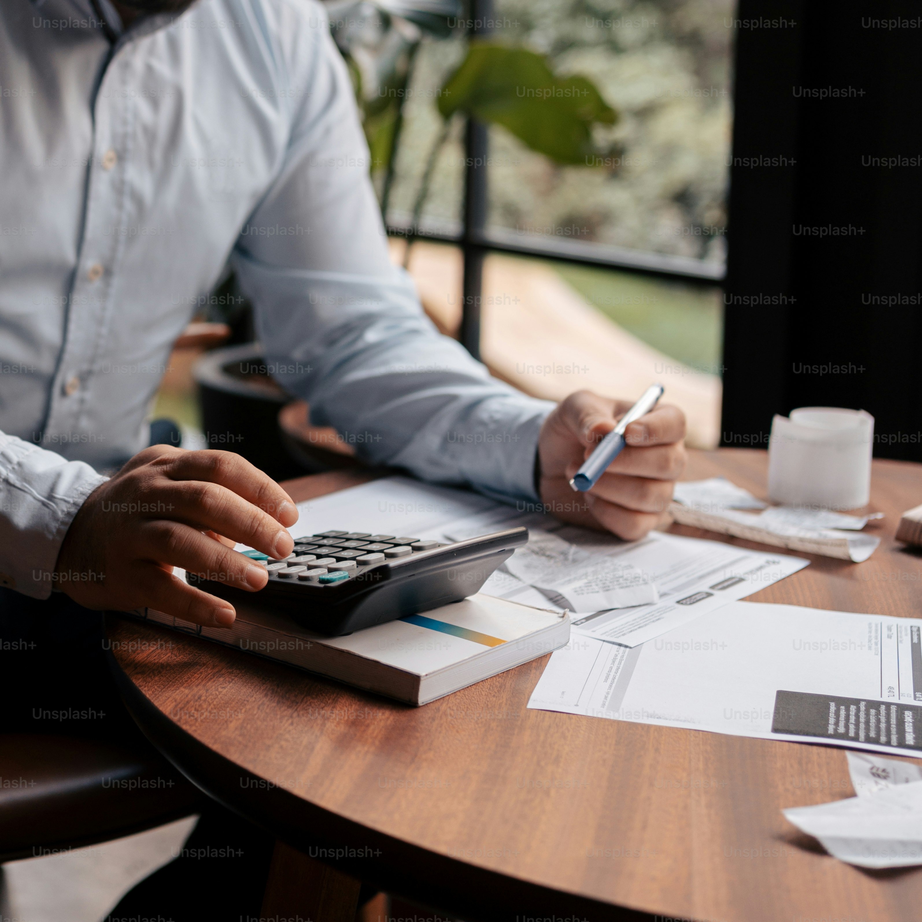 A man sitting at a table with a calculator photo – Finances Image on ...