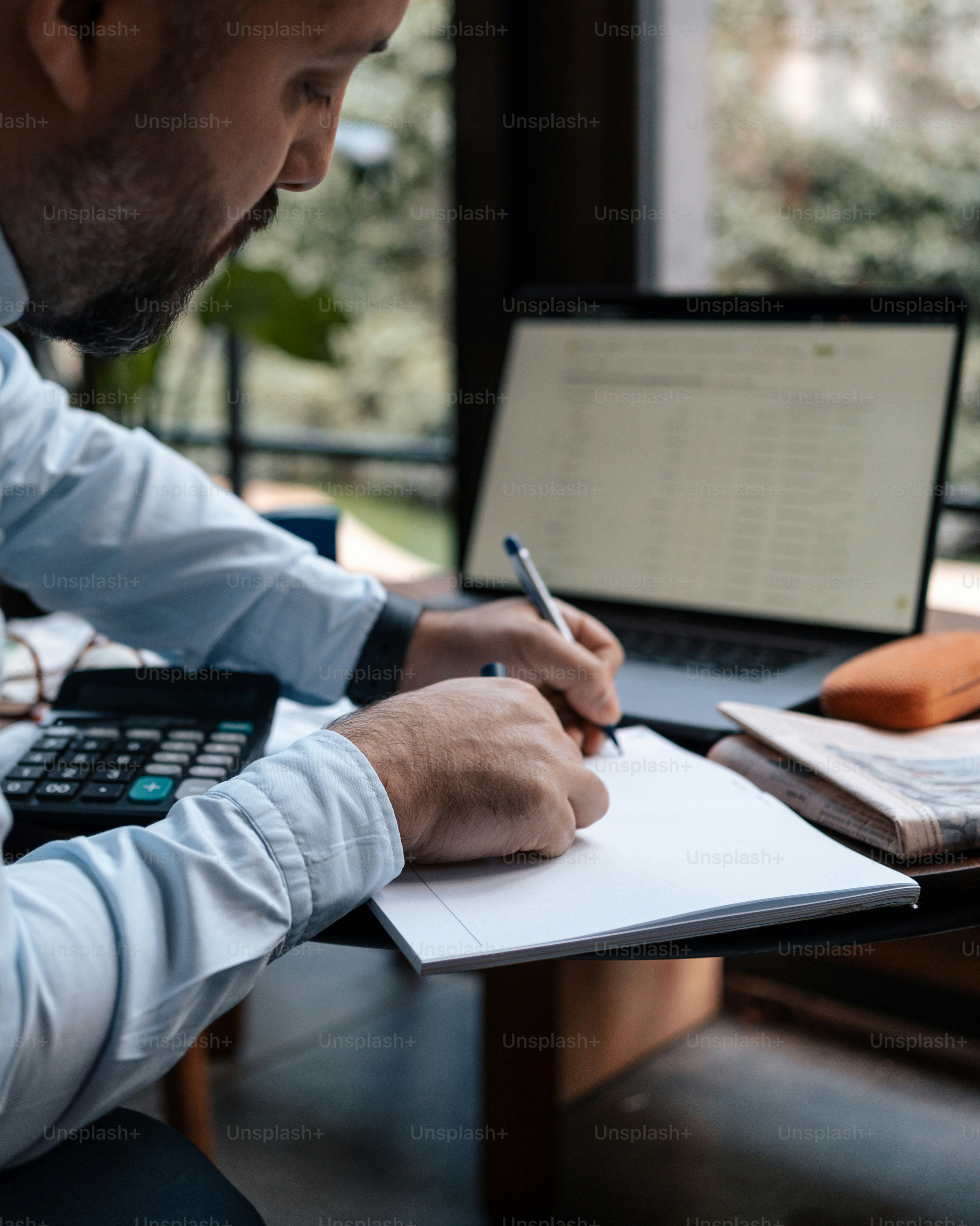 A man sitting at a table with a calculator photo – Finances Image on ...
