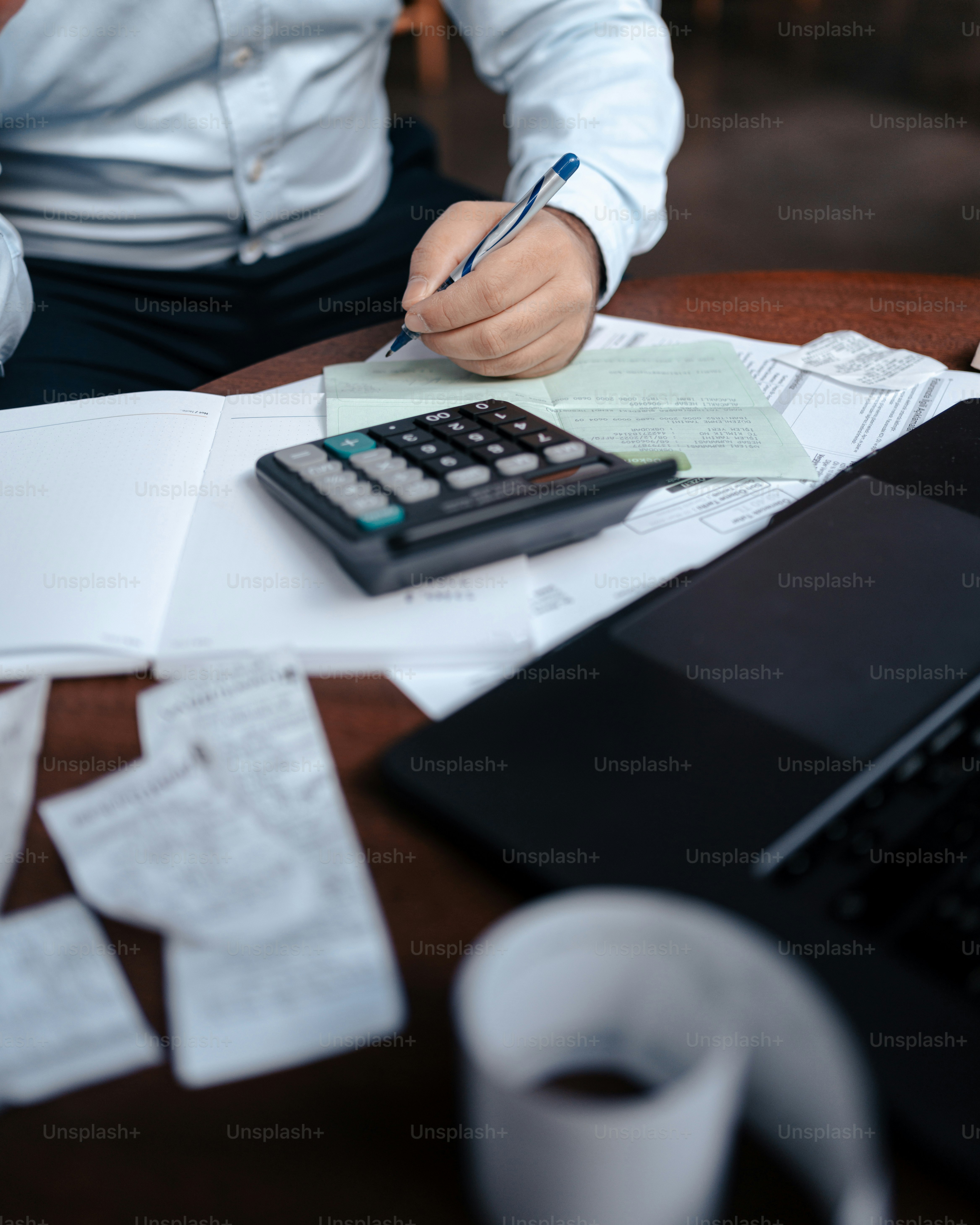 A person sitting at a table with a calculator and a laptop photo – Left ...