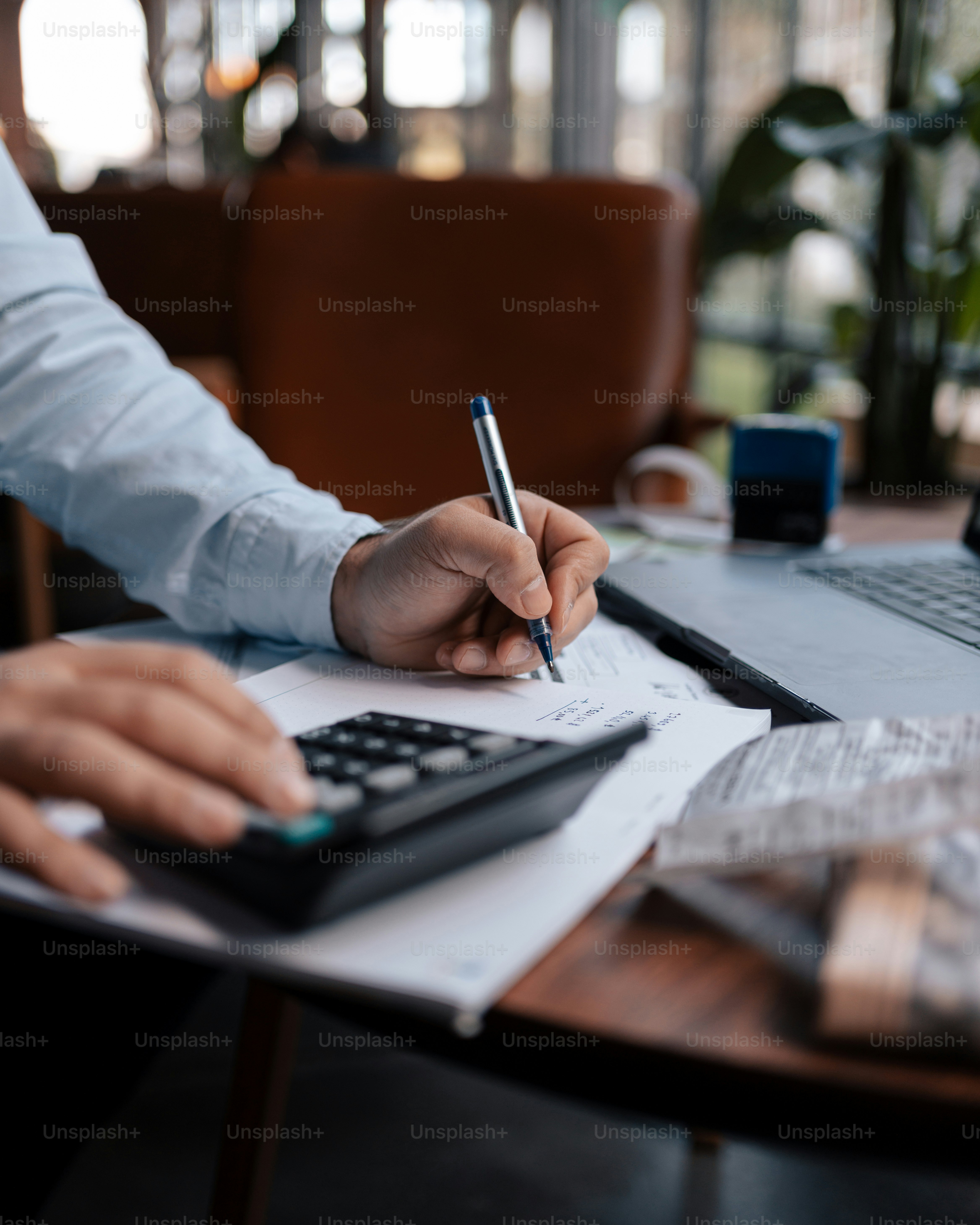 A person sitting at a desk with a laptop and a calculator photo – Taxes ...