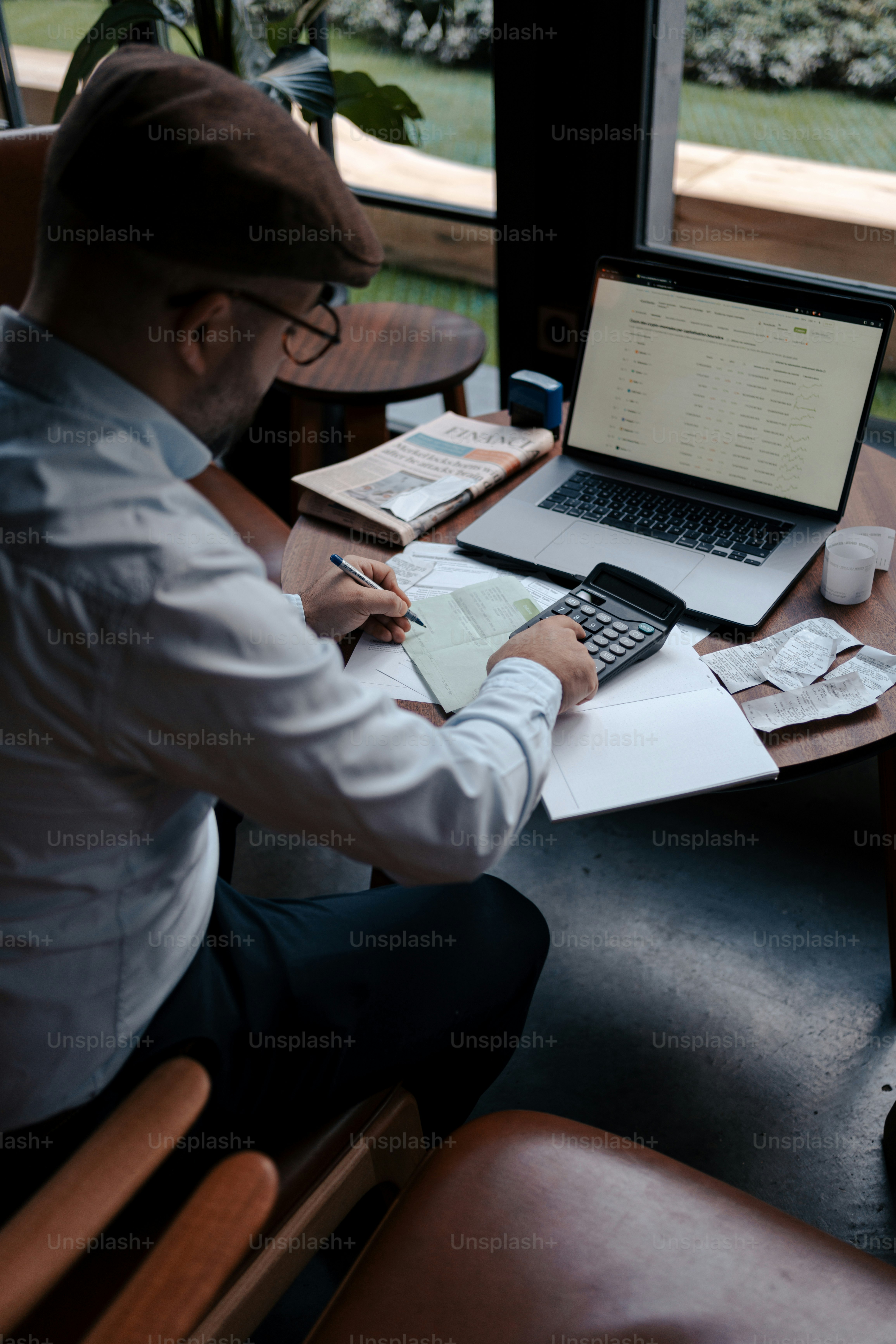 A man sitting at a table with a calculator photo – Finances Image on ...