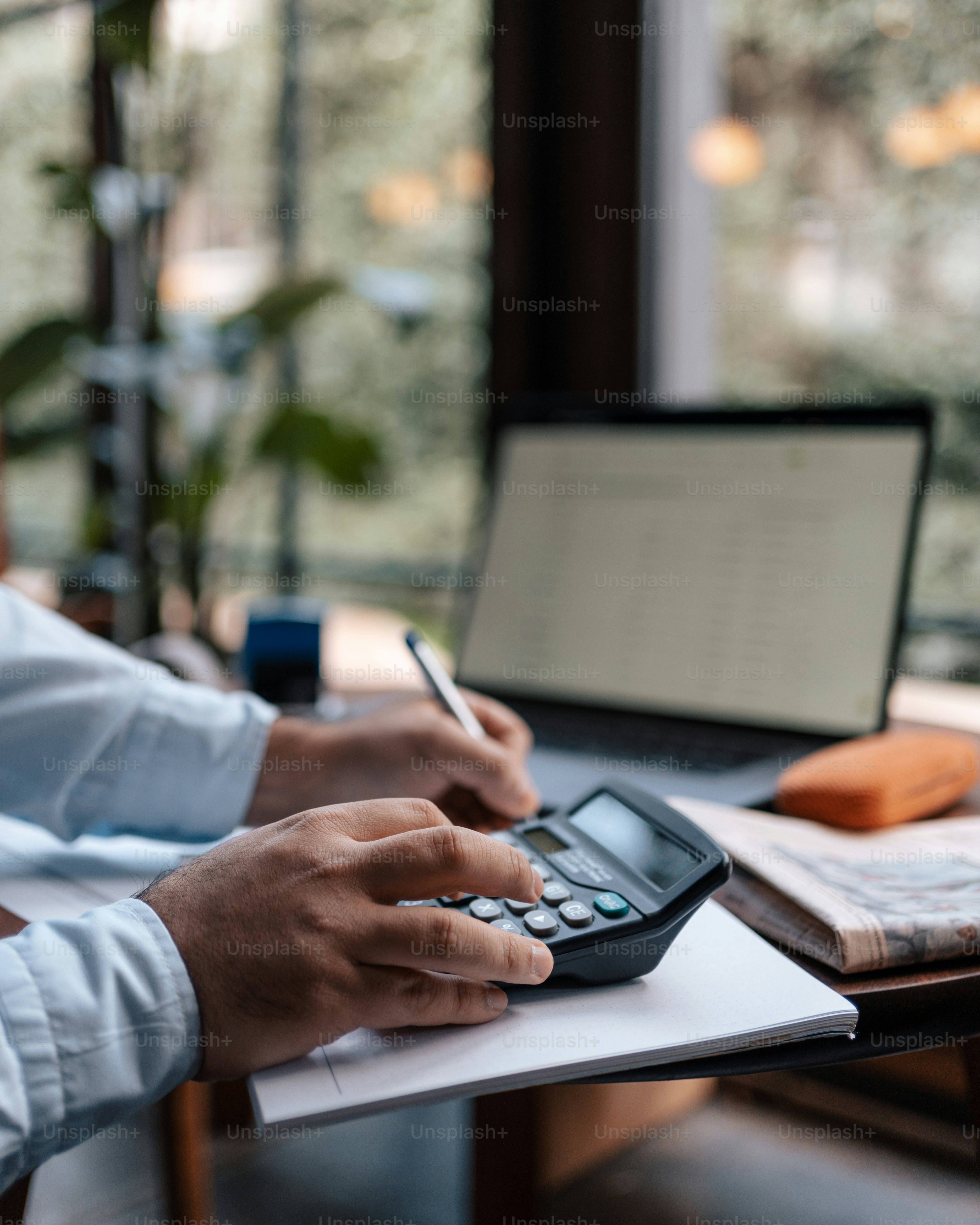 A man sitting at a table with a calculator photo – Finances Image on ...