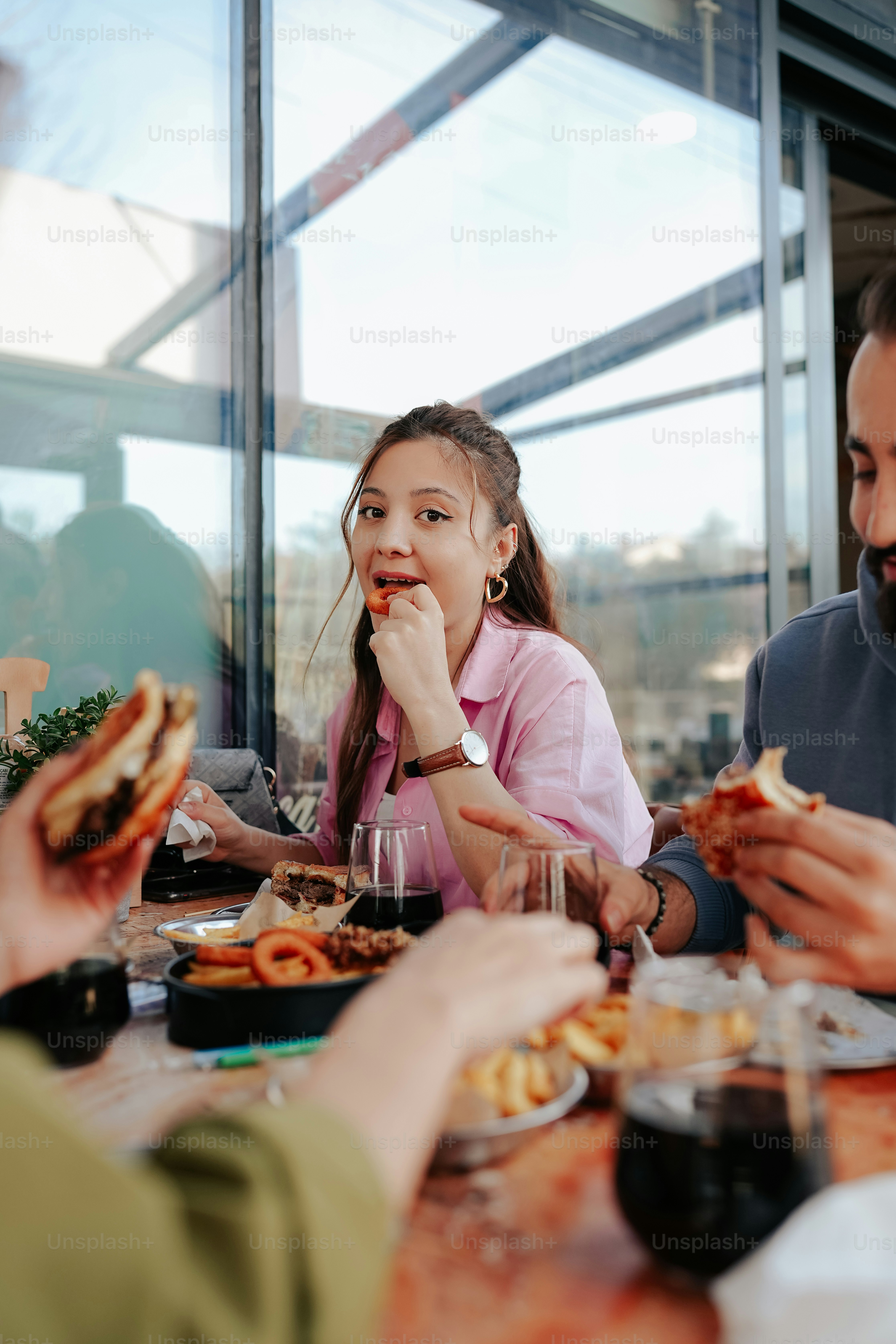 A group of people sitting around a table eating food photo – Woman ...