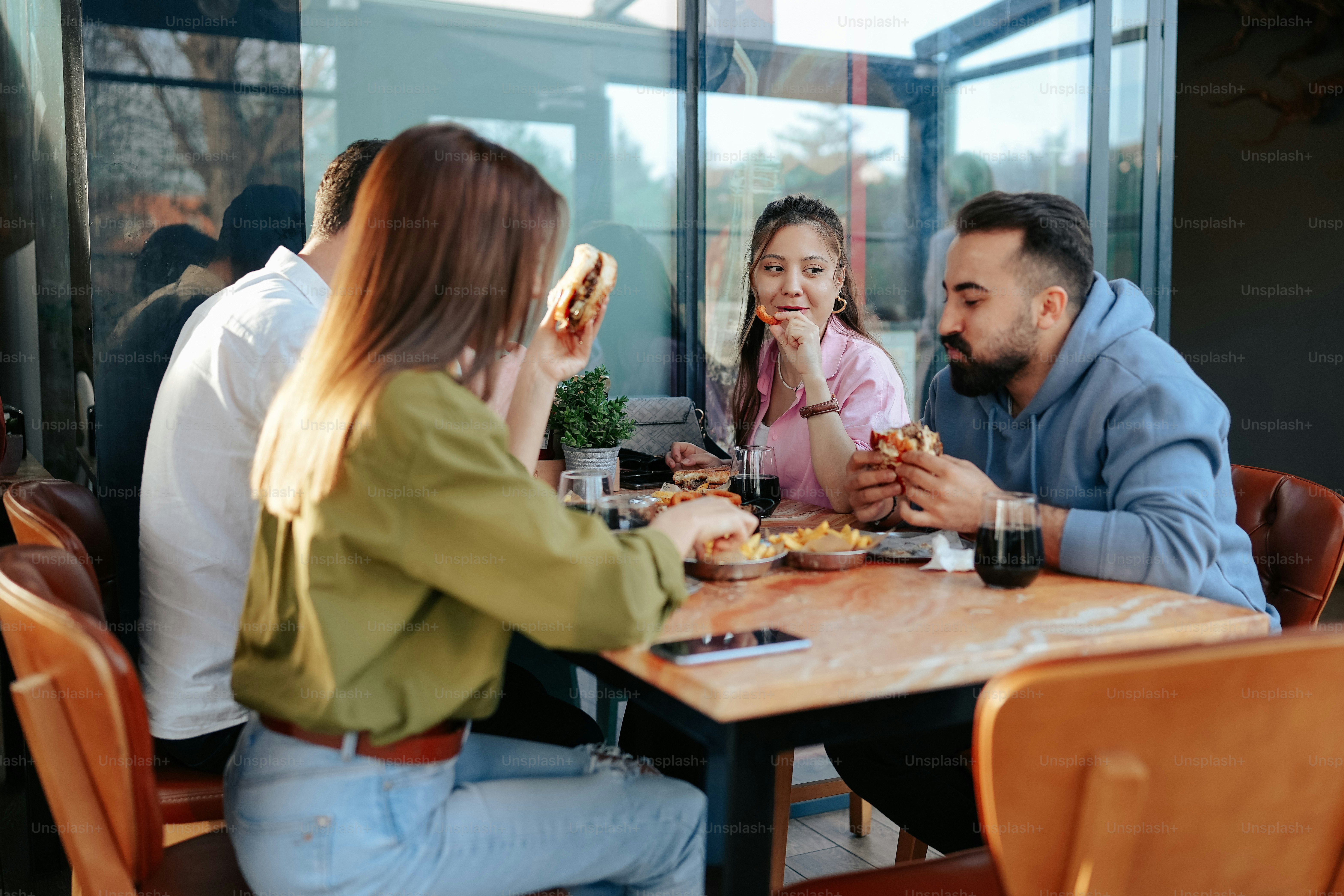 A group of people sitting around a table eating food photo – Brunch ...