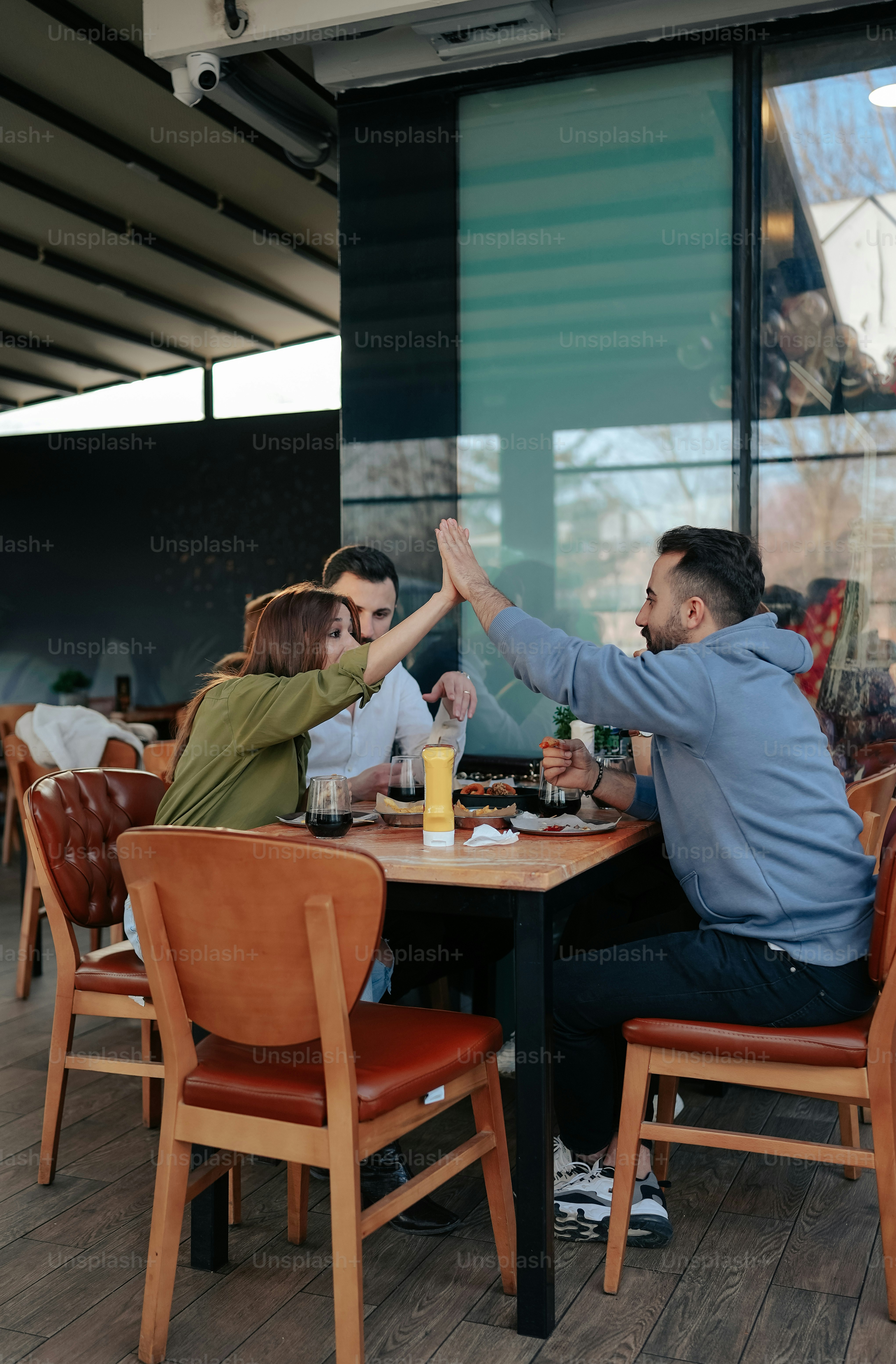 A man and woman sitting at a table high five each other photo – Food ...