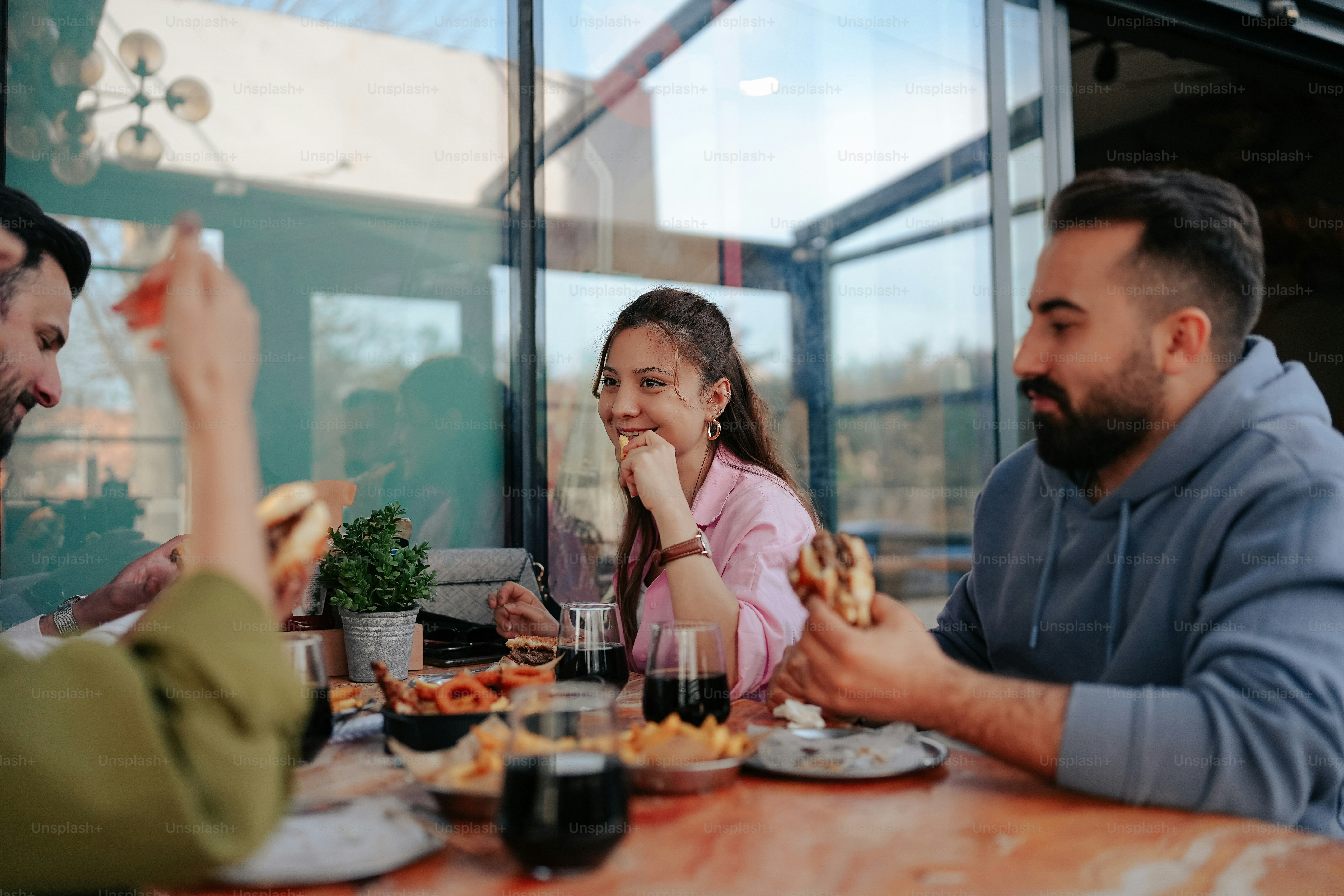 A group of people sitting around a table eating food photo – Restaurant ...