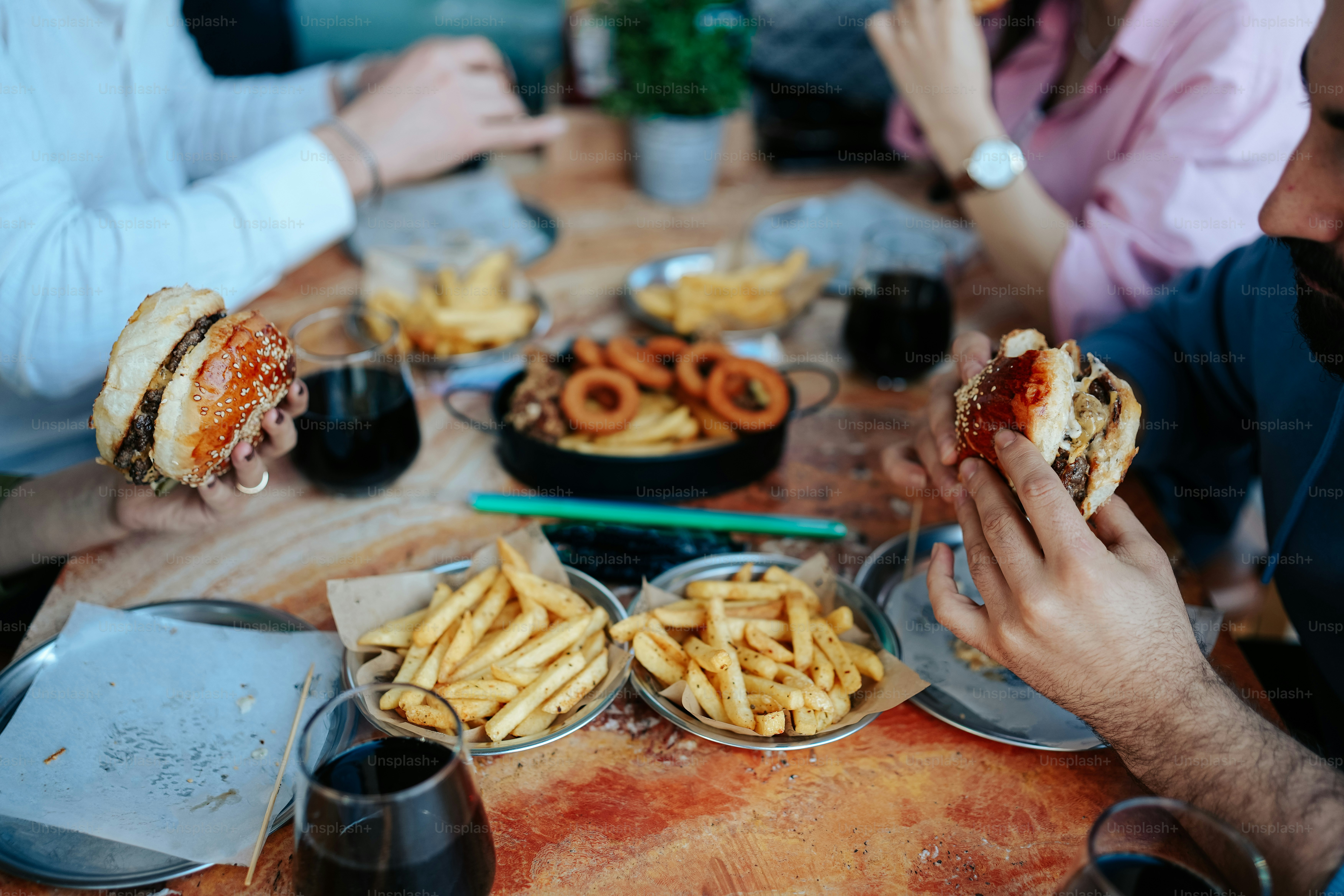 A group of people sitting around a table eating food photo – Restaurant ...