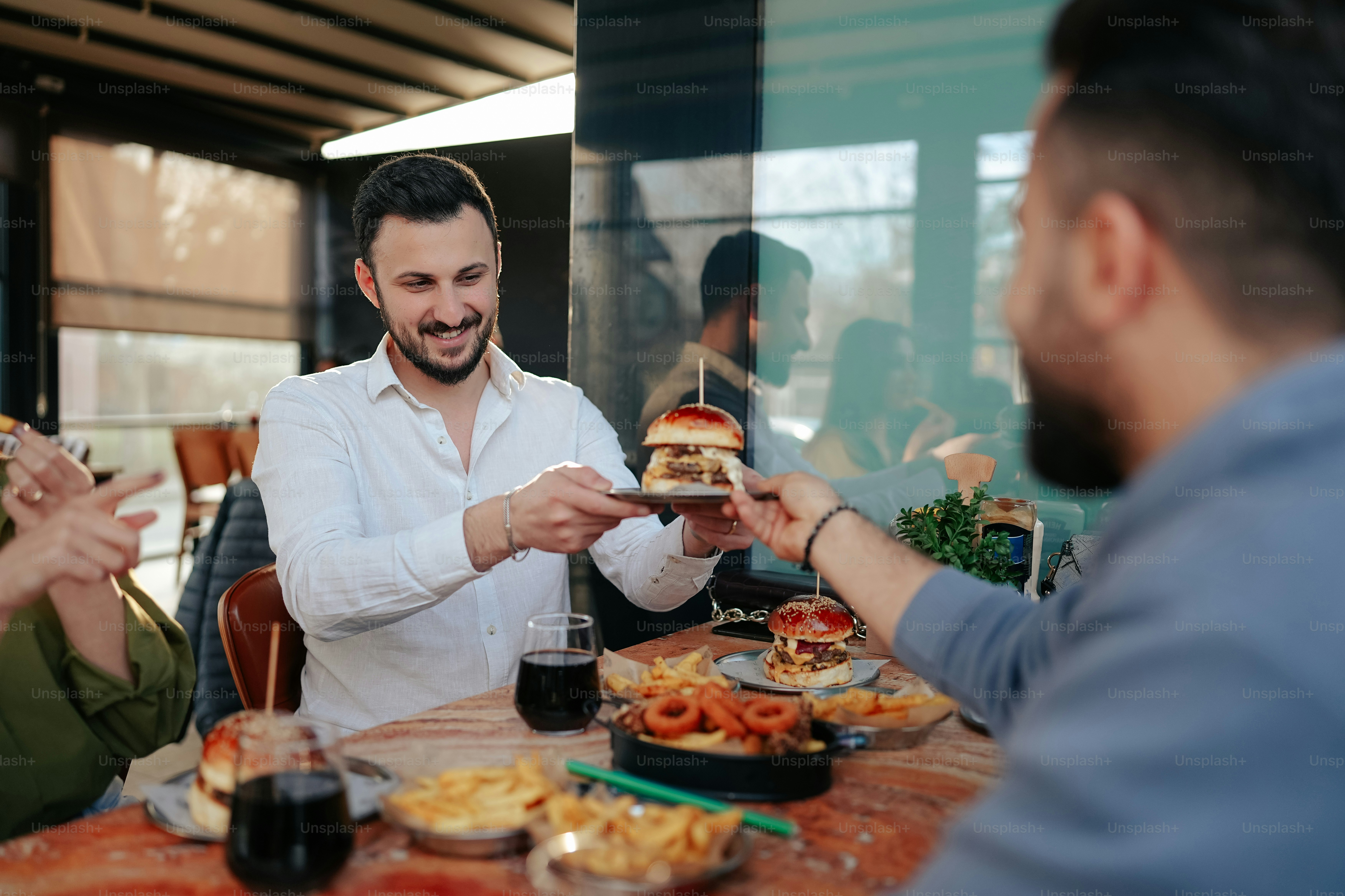 A group of people sitting around a table eating food photo – Restaurant ...