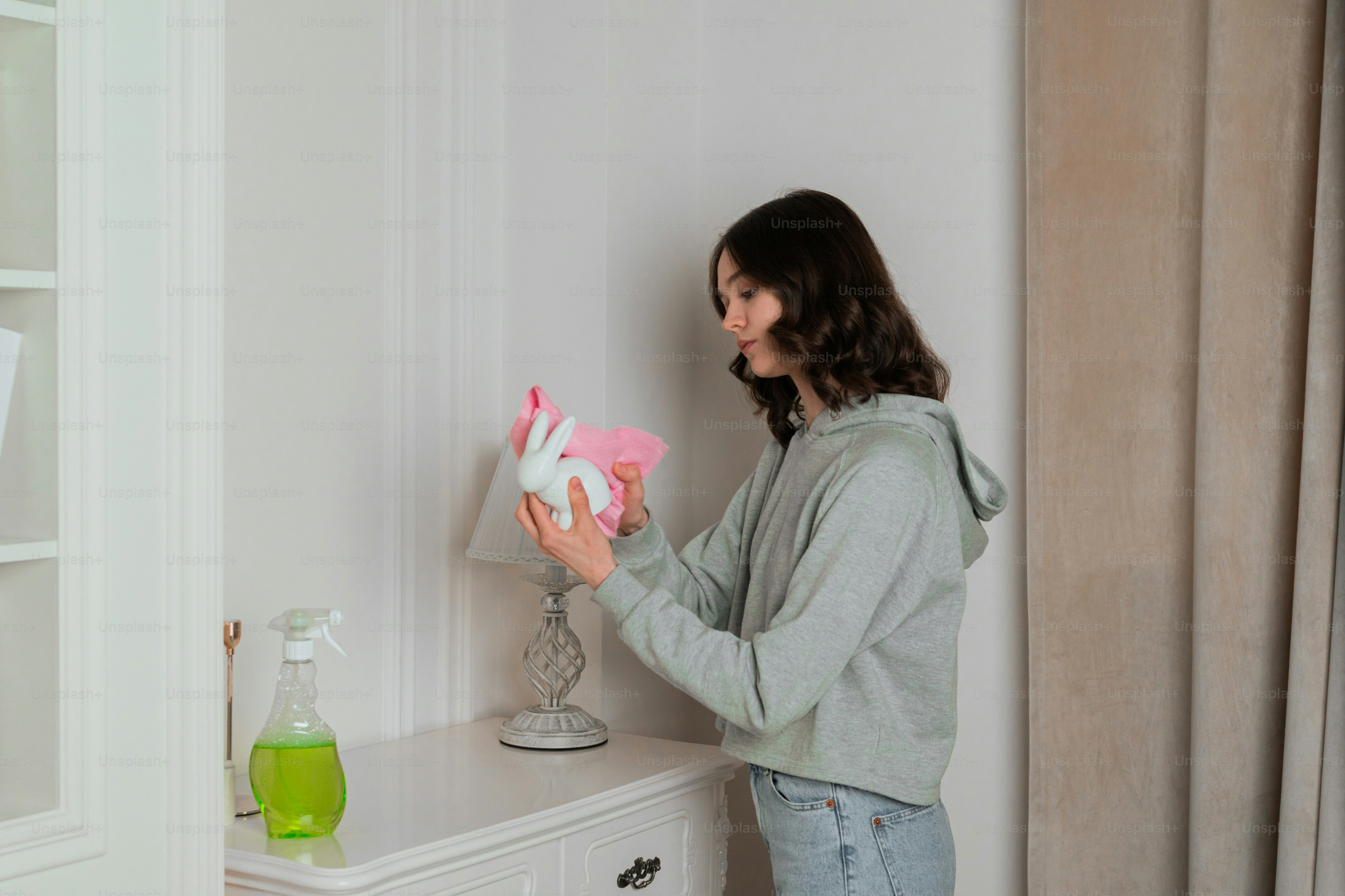 A woman holding a pink object in her hand photo – Spring cleaning Image ...
