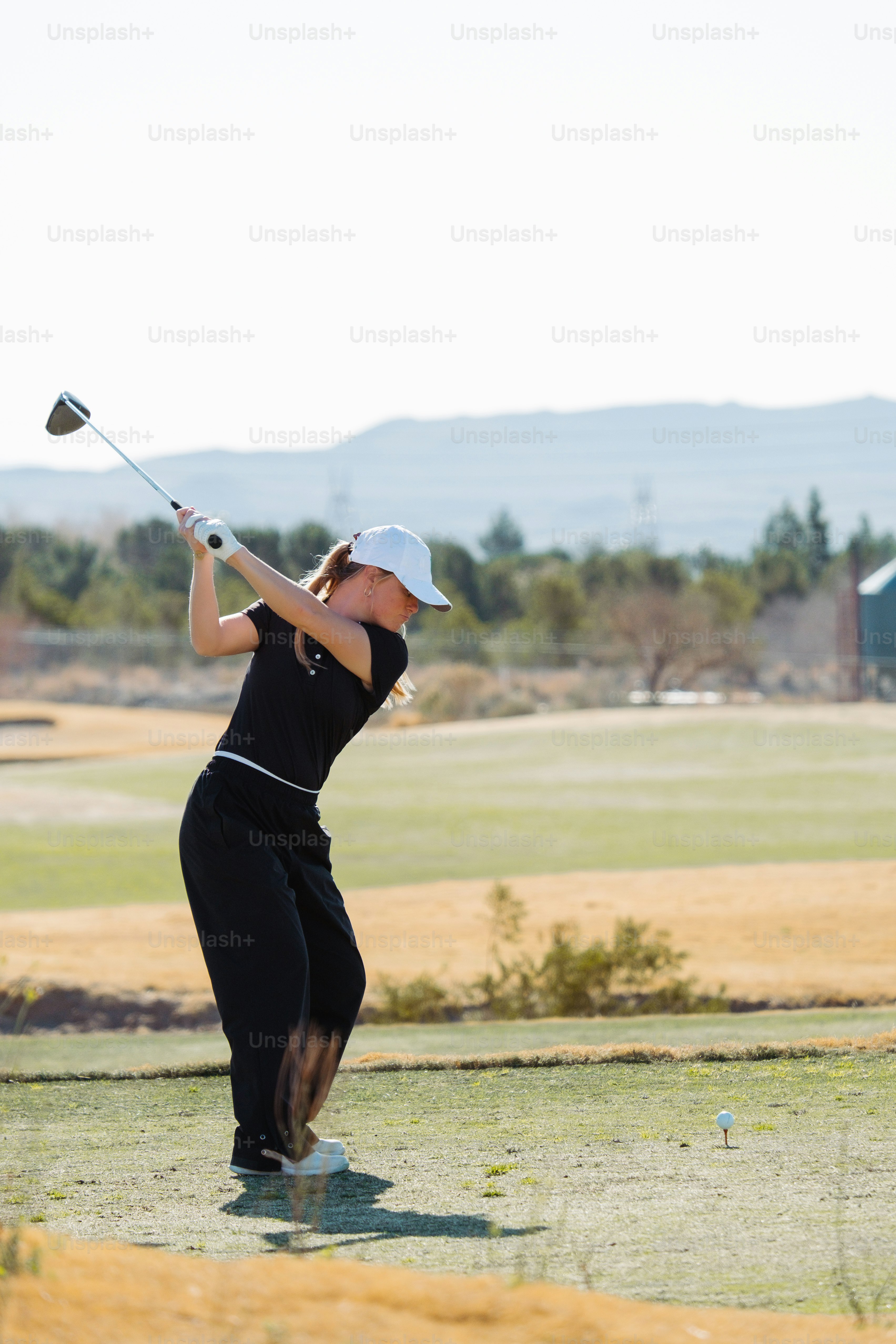 A woman swinging a golf club on a golf course photo – Golfing Image on ...