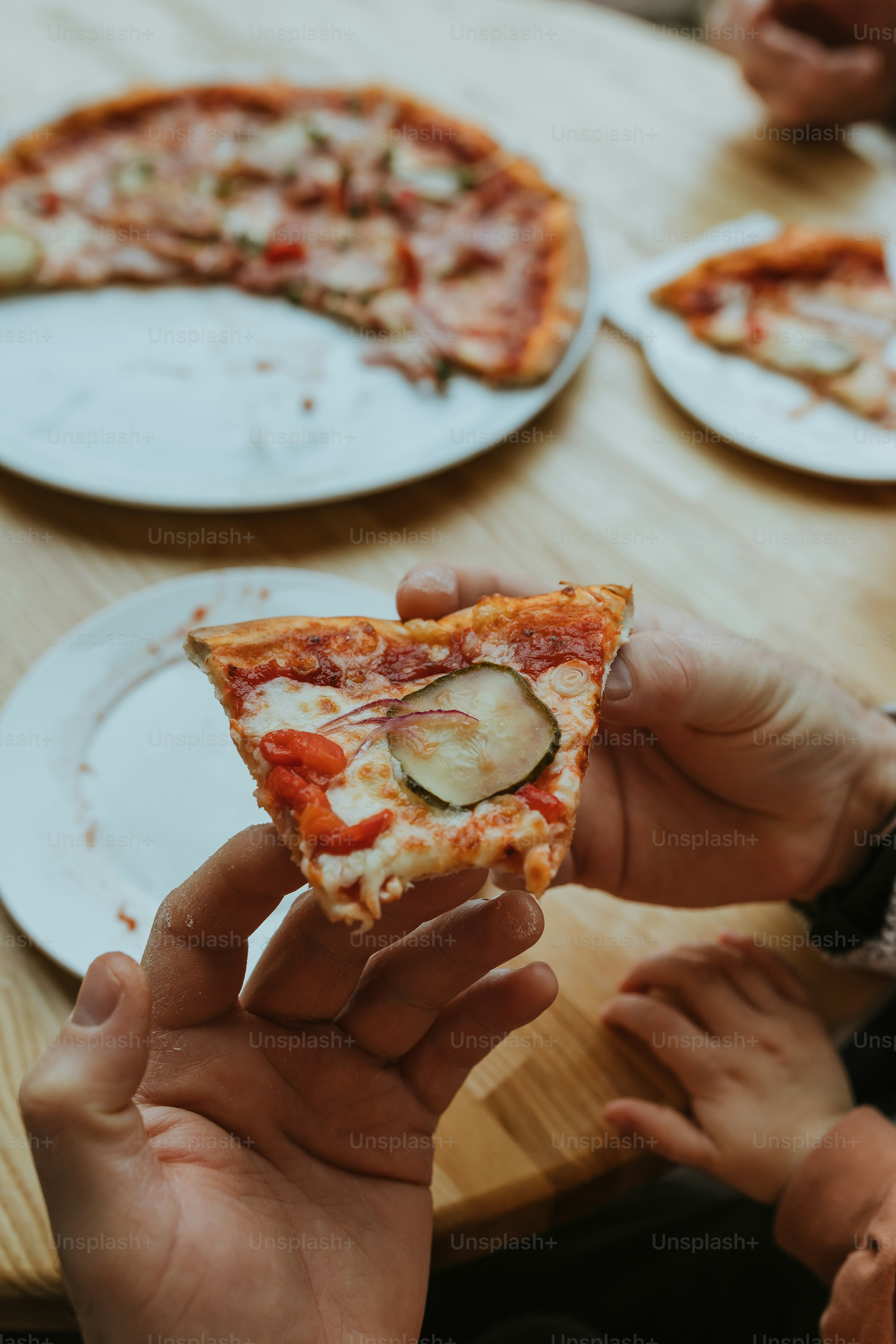 A group of people sitting around a table with pizza photo – Dinner ...