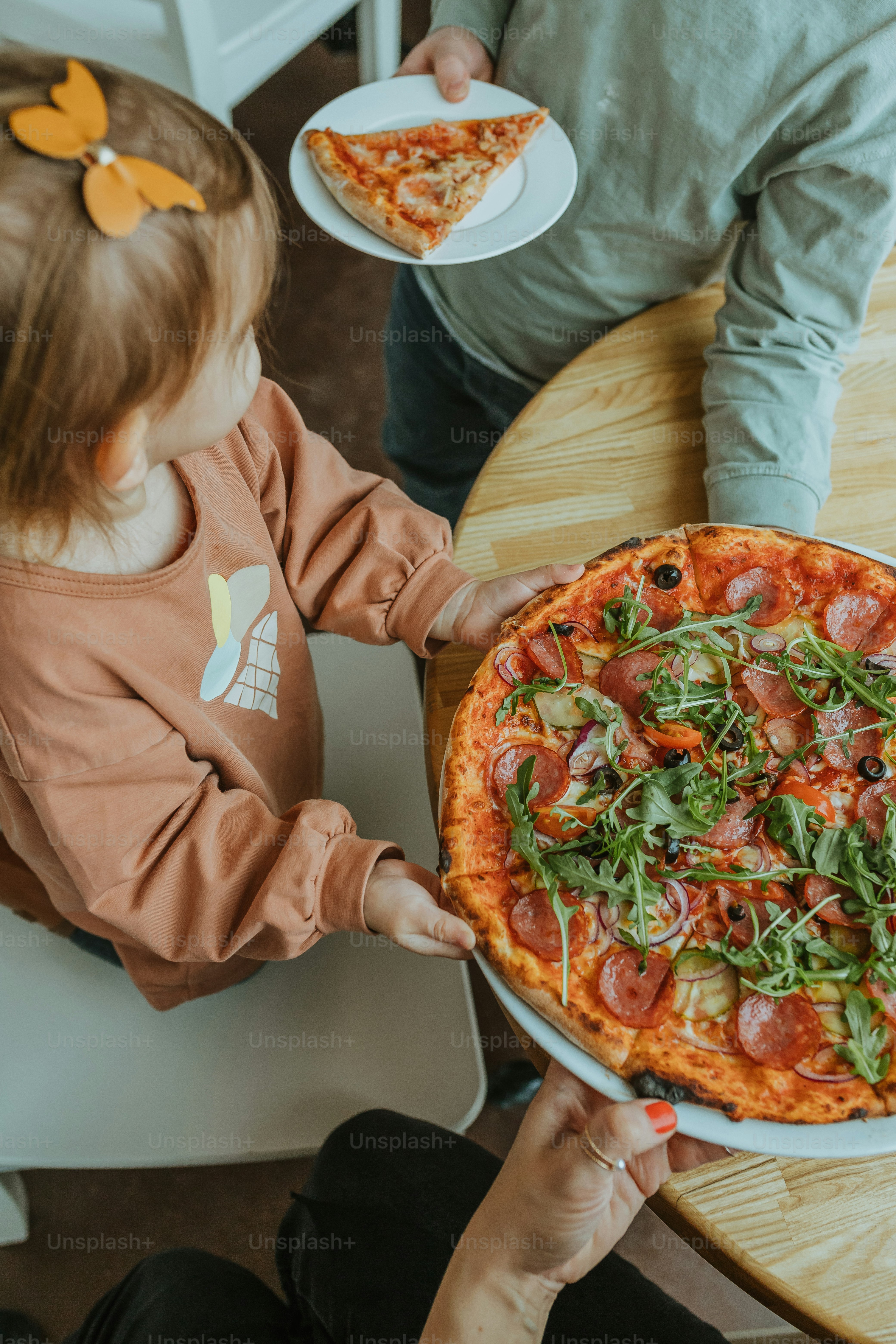 A group of people sitting around a table with pizza photo – Dinner ...