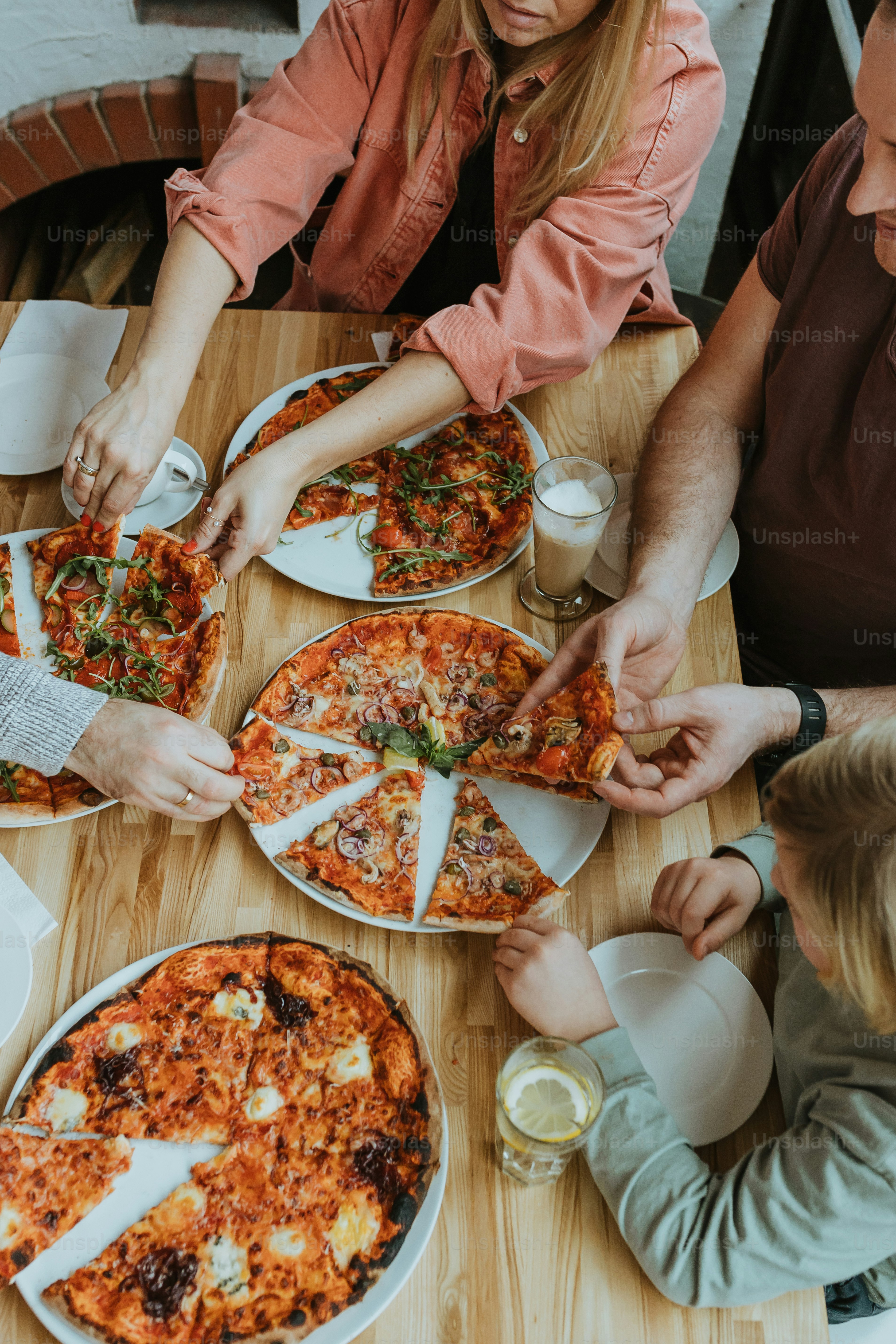 A group of people sitting around a table with pizza photo – Dinner ...