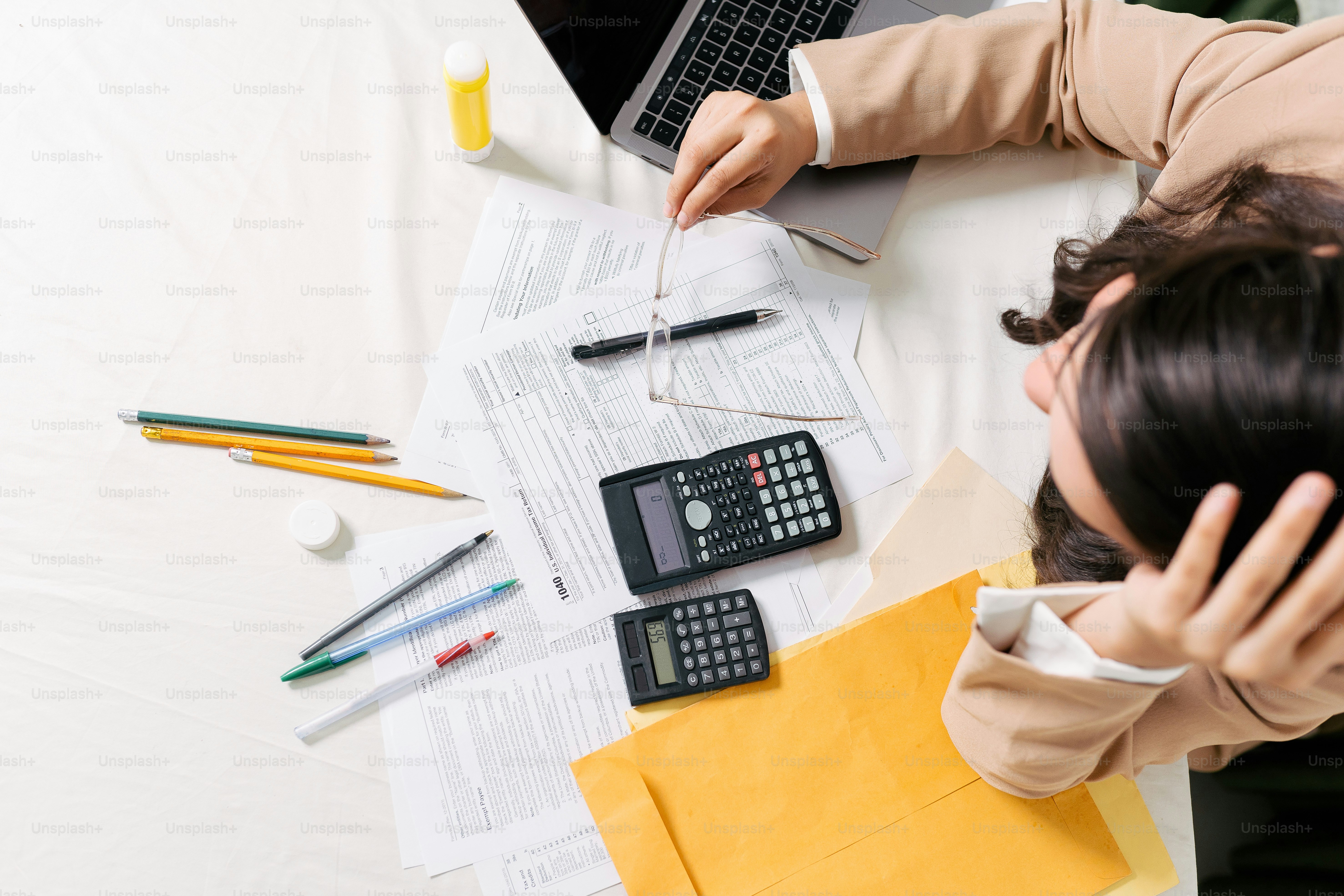 A person sitting at a table with a laptop and calculator photo ...