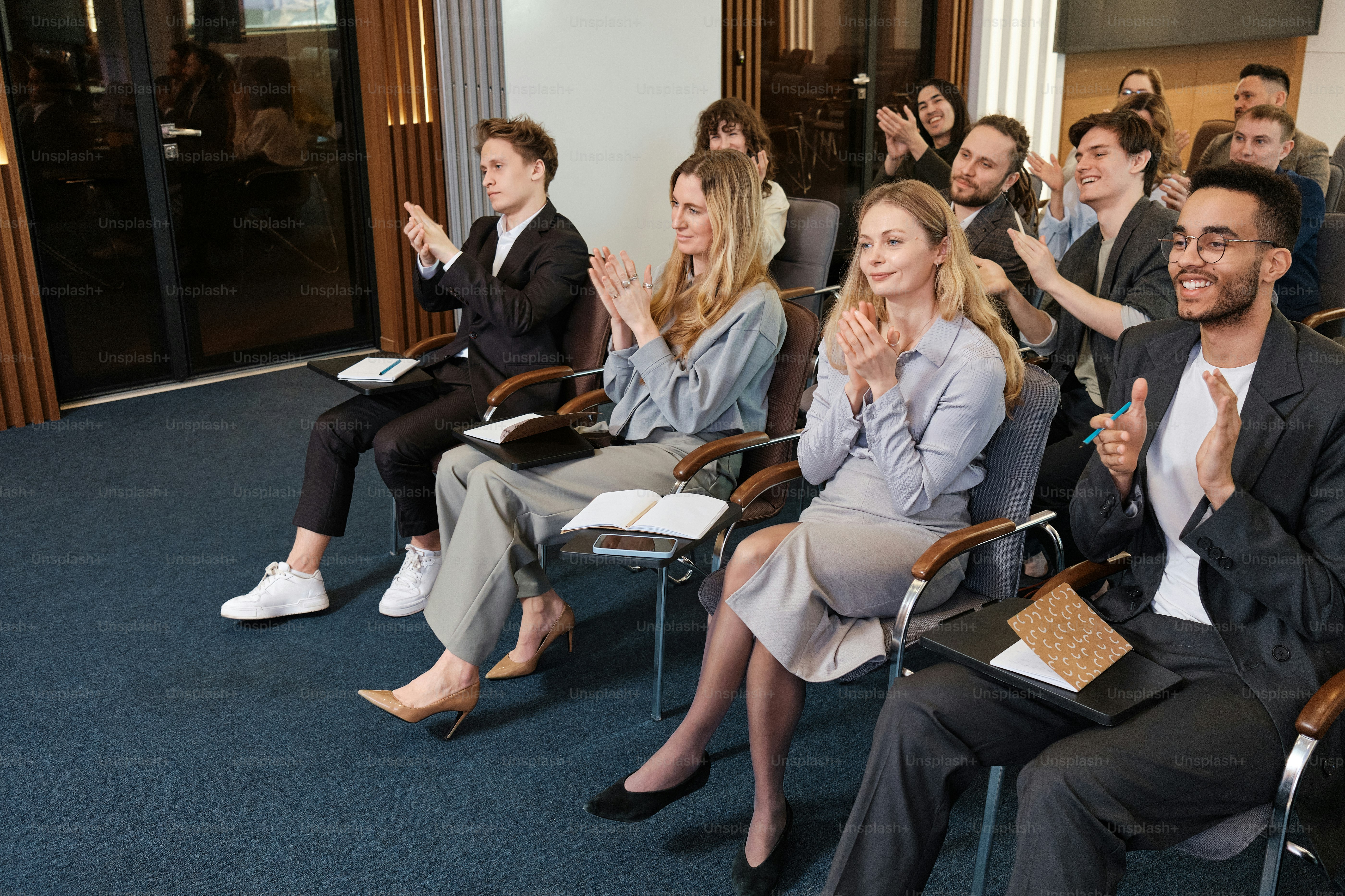 A group of people sitting in chairs clapping photo – Applause Image on ...