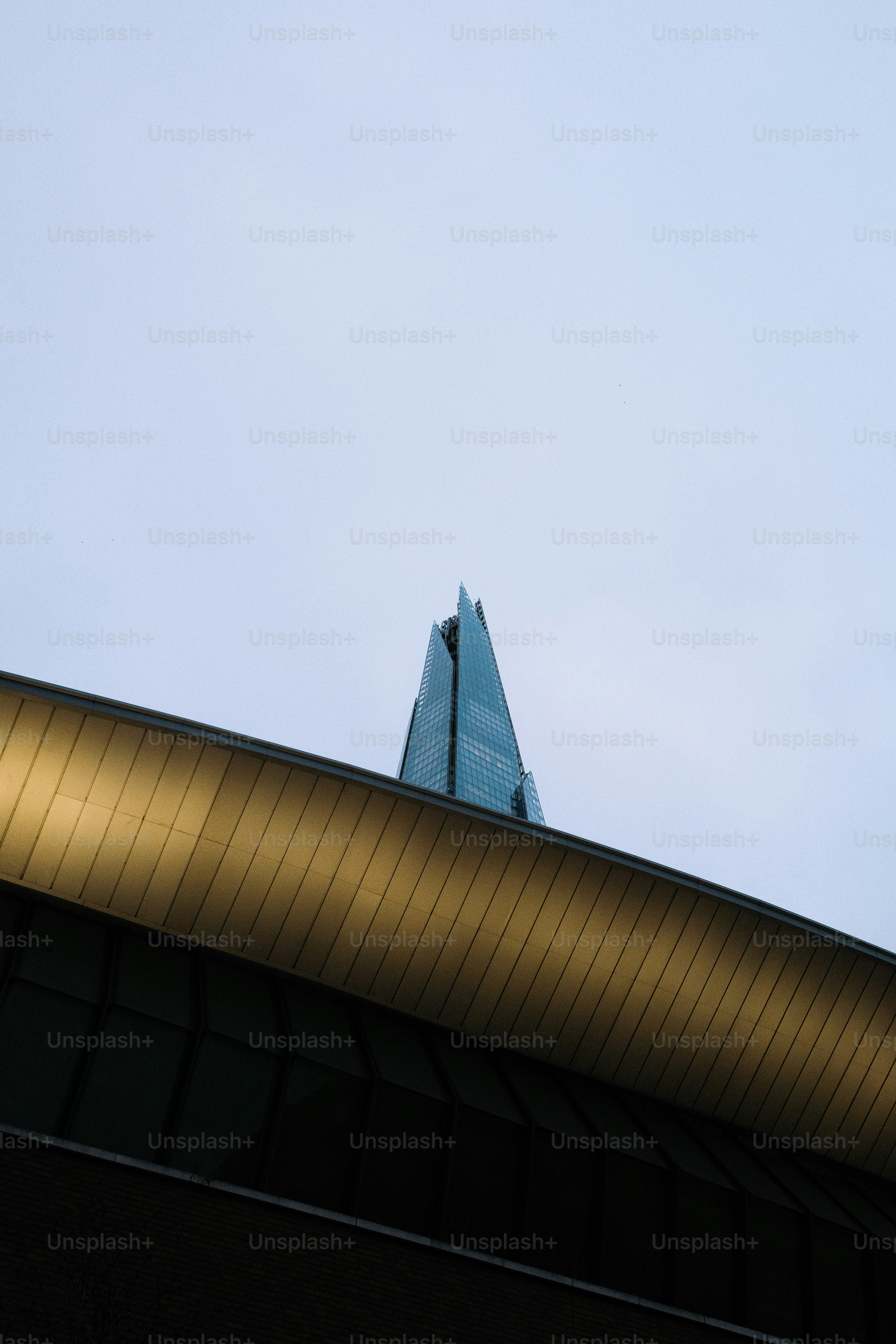 A building with a triangular roof and a sky background photo – London ...