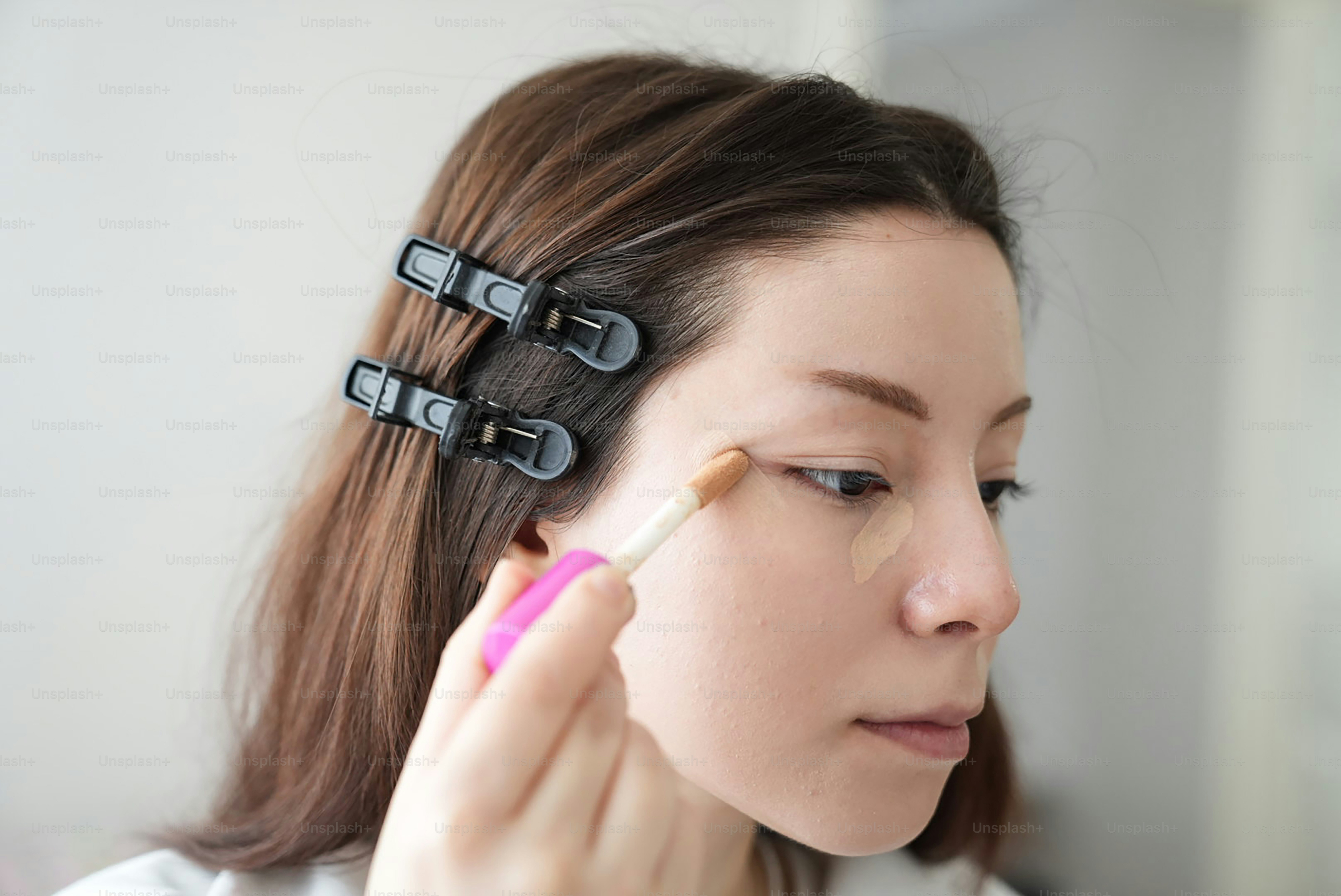 A woman is putting conceal on her face photo – Eyelids Image on Unsplash